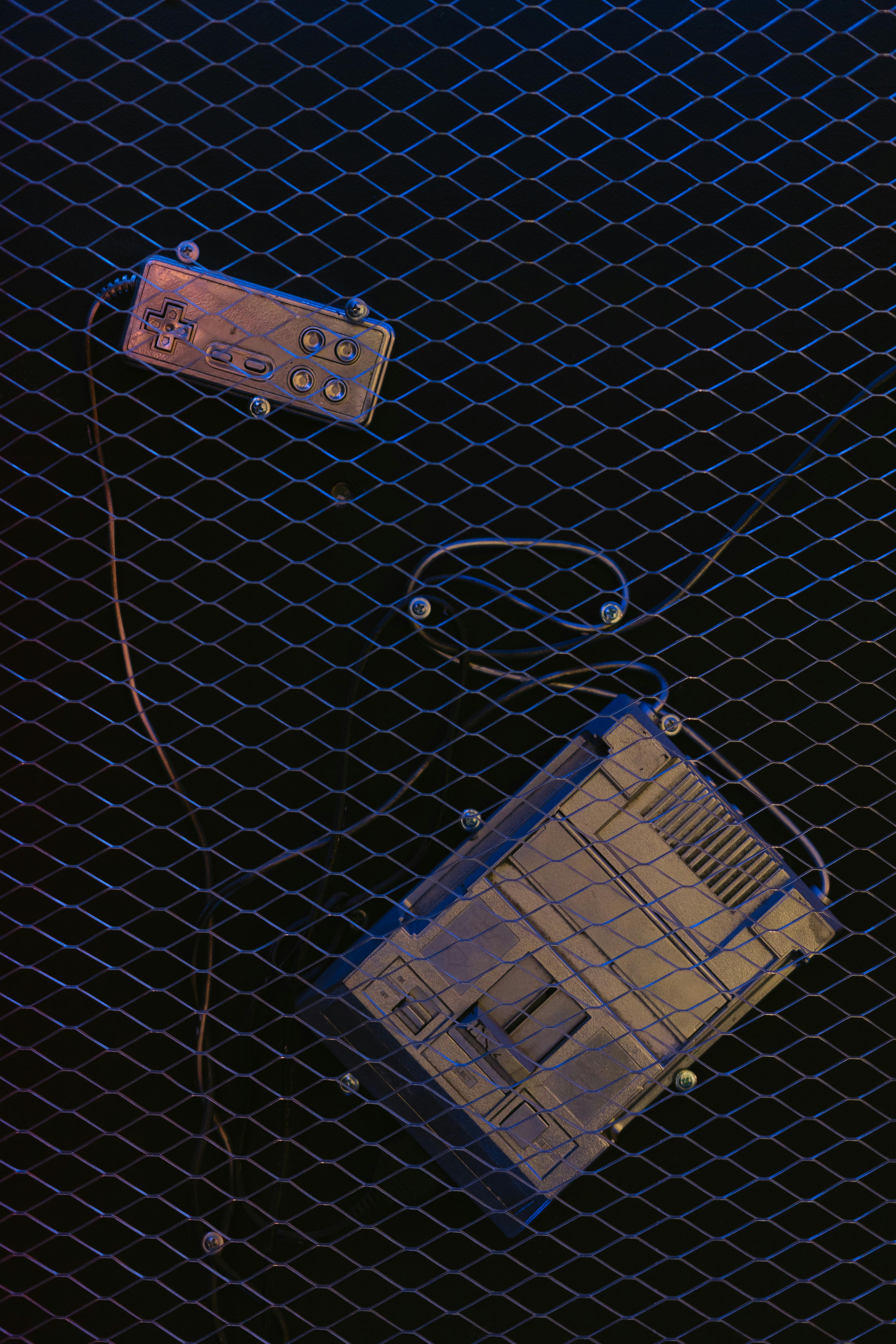 Video Game Console Hanging on a Wire Mesh · Free Stock Photo