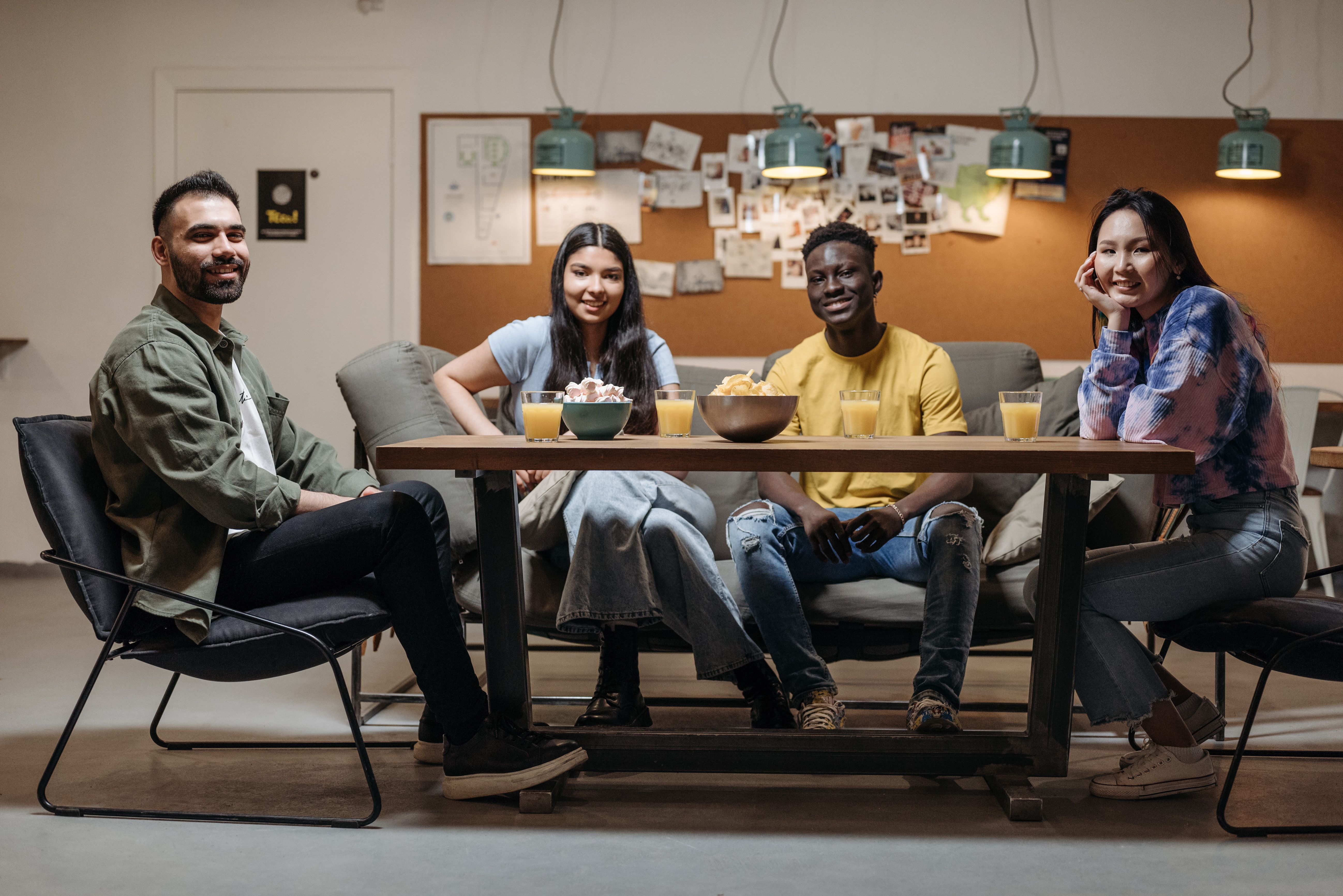 Smiling Friends Sitting by Table in Living Room · Free Stock Photo