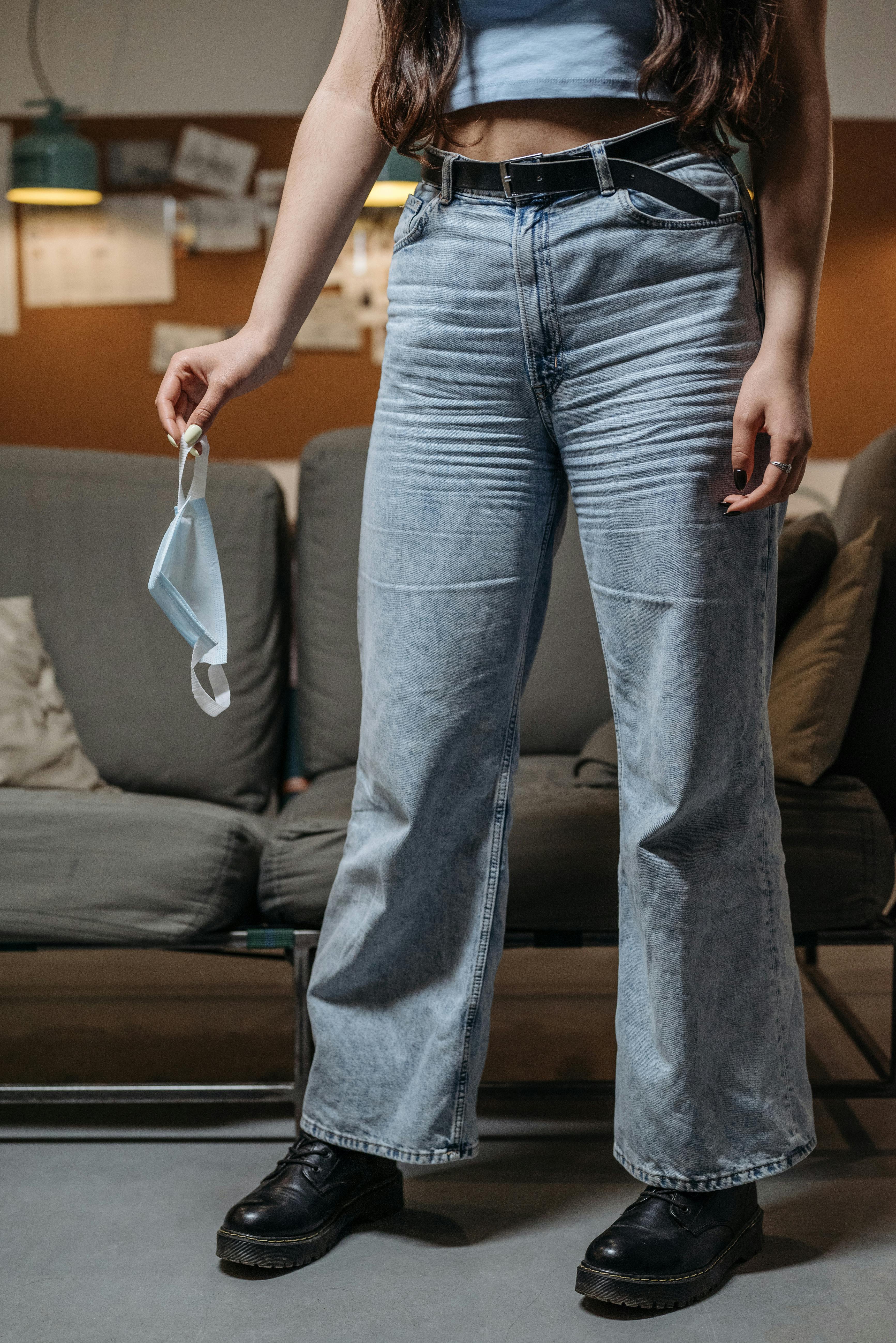 Person In Blue Jeans Holding a Face Mask · Free Stock Photo