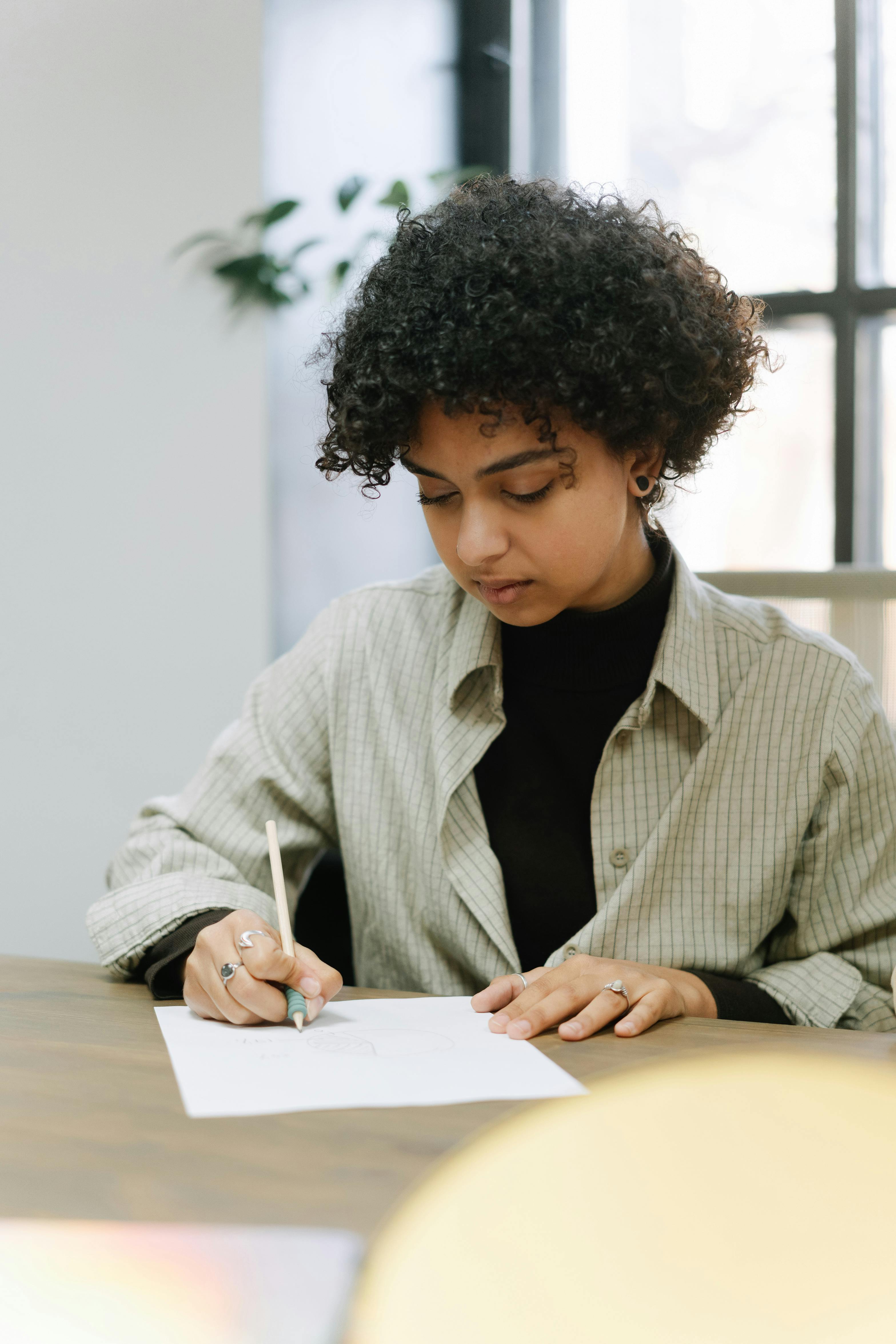 A Woman Sitting and Writing on a Paper · Free Stock Photo