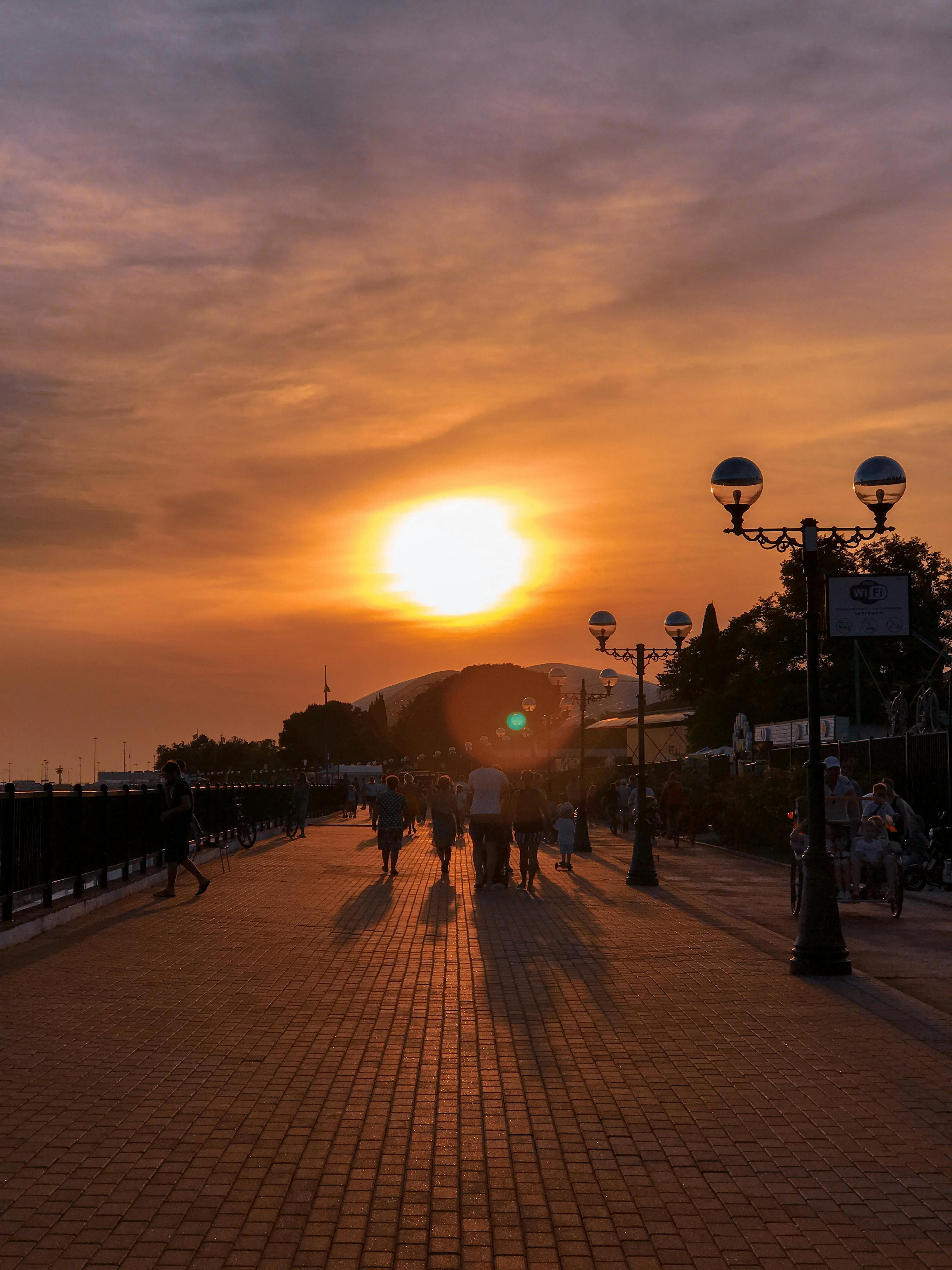 People Walking on a Sidewalk at Sunset · Free Stock Photo