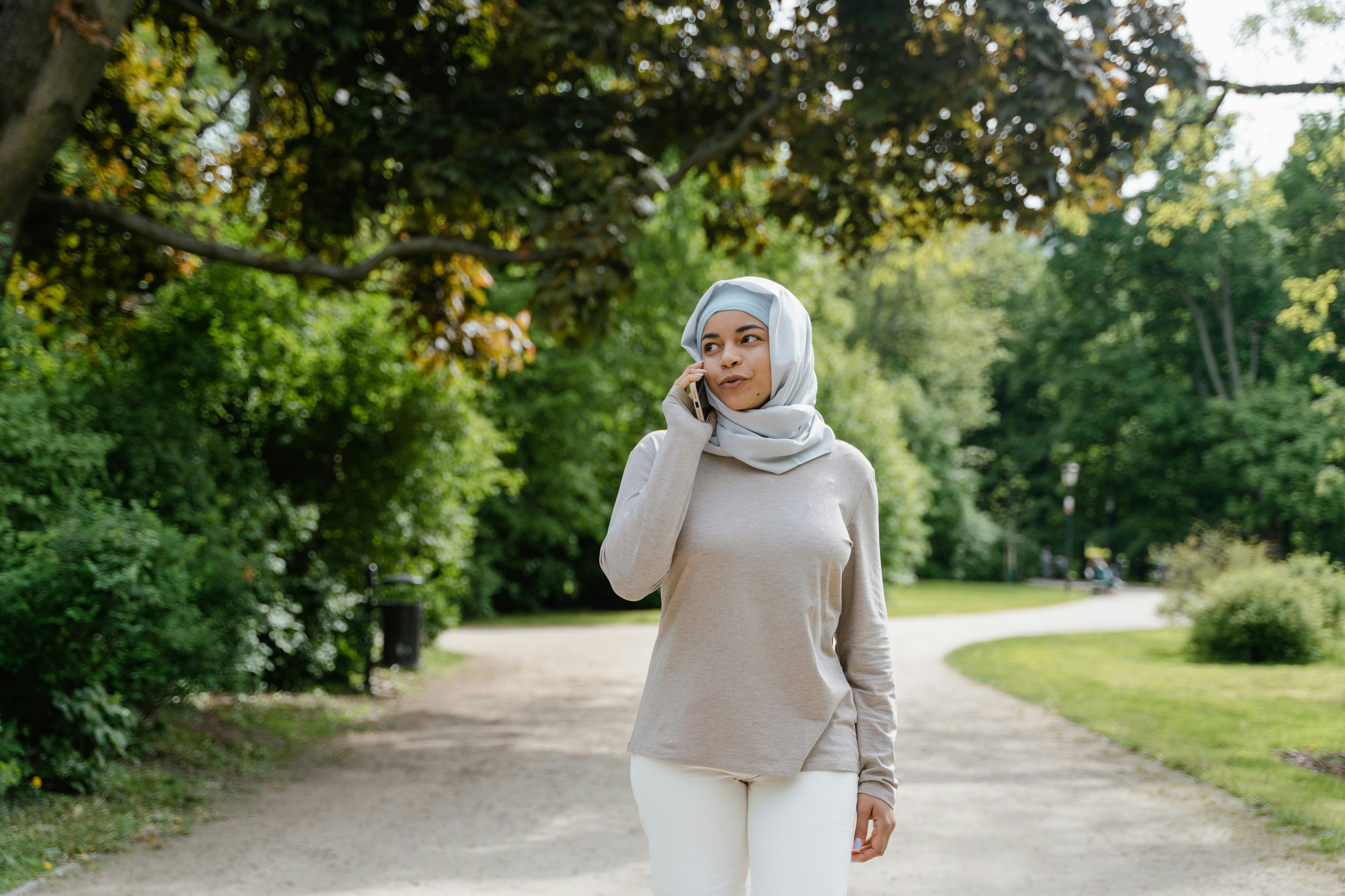 A Woman Talking on the Phone while Walking on the Park · Free Stock Photo