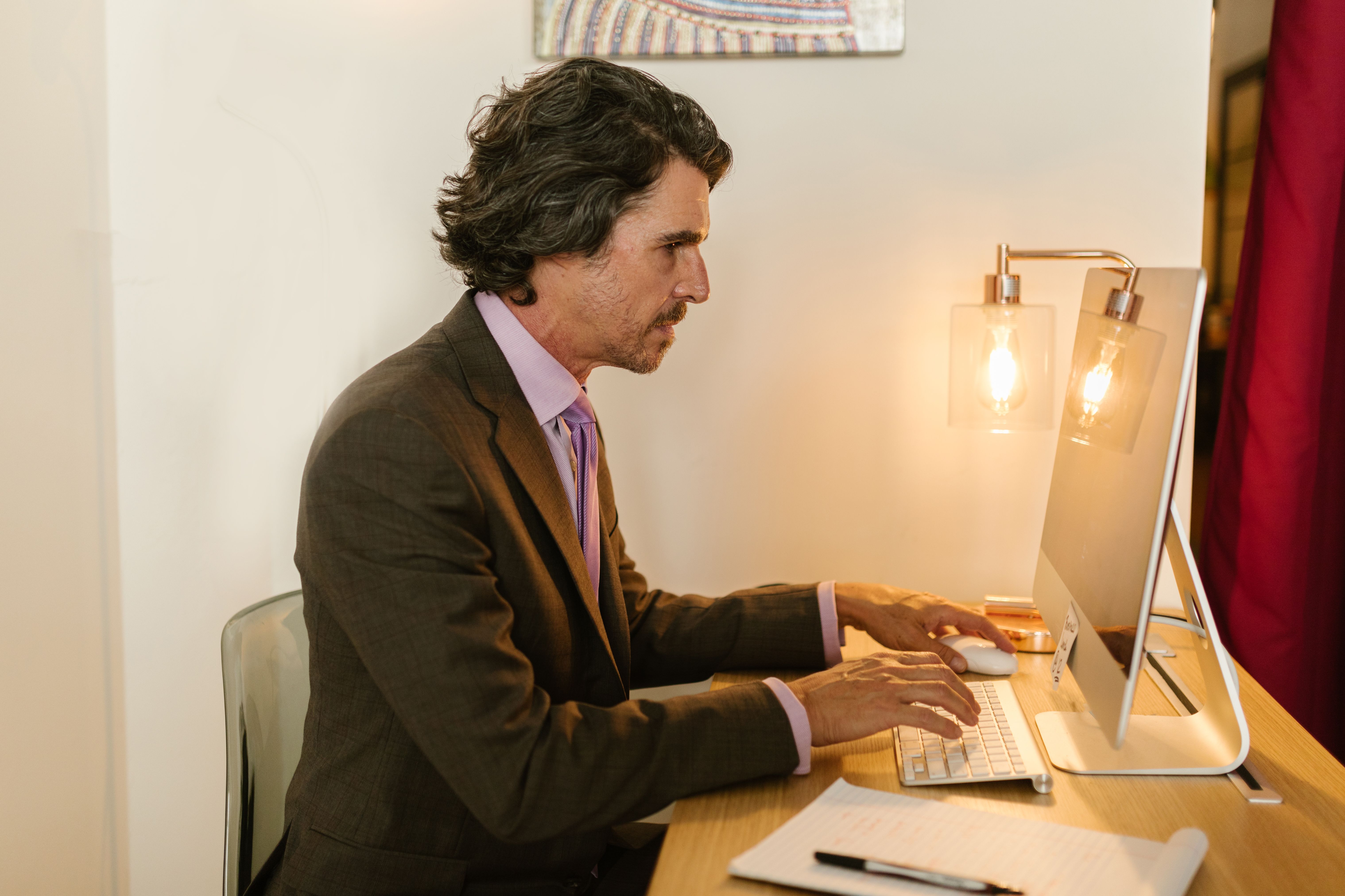 A Man in Gray Suit Typing while Looking at the Monitor · Free Stock Photo