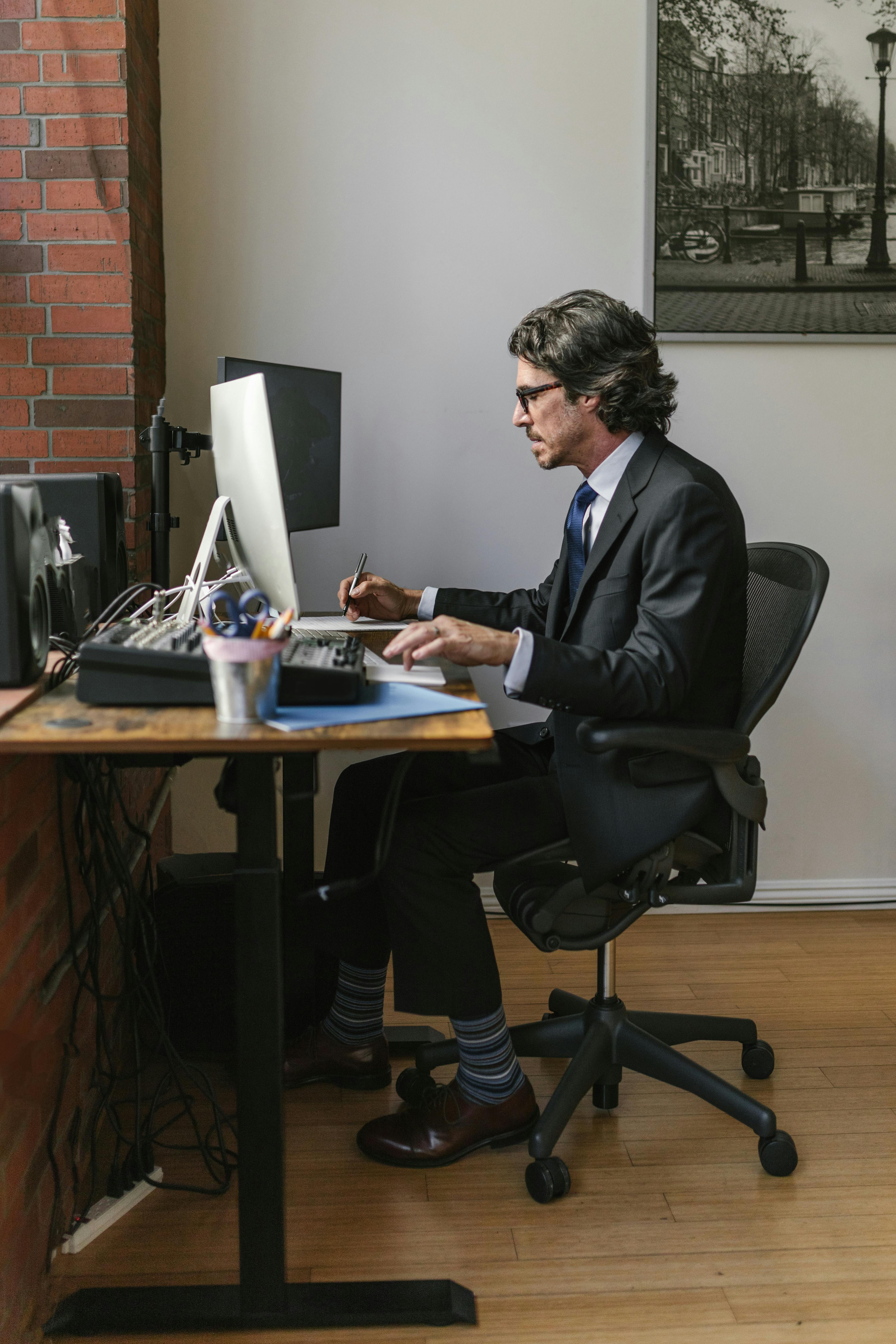 Man in Black Suit Sitting on a Desk Chair · Free Stock Photo
