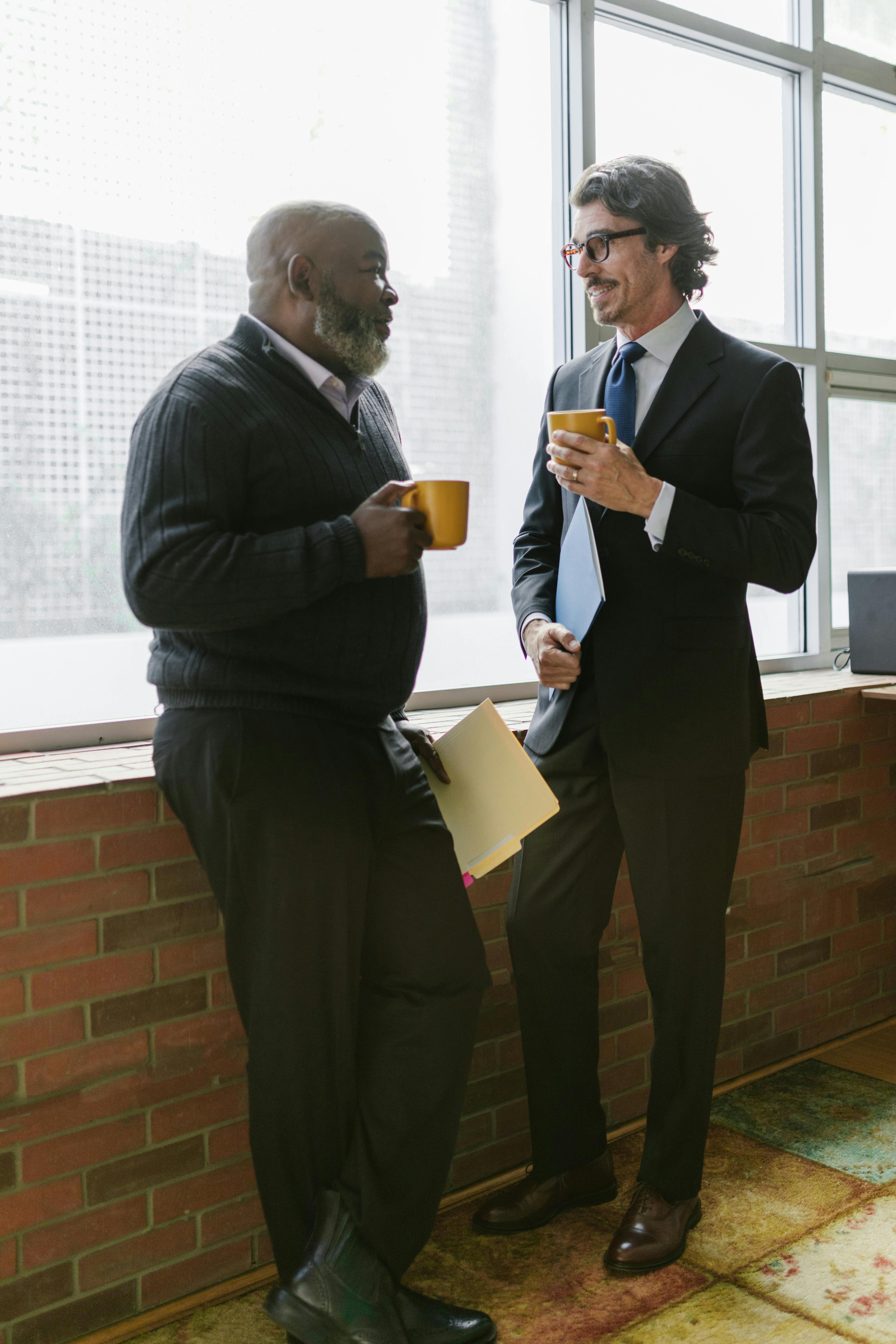 Men Having Conversation while Standing Near the Window · Free Stock Photo