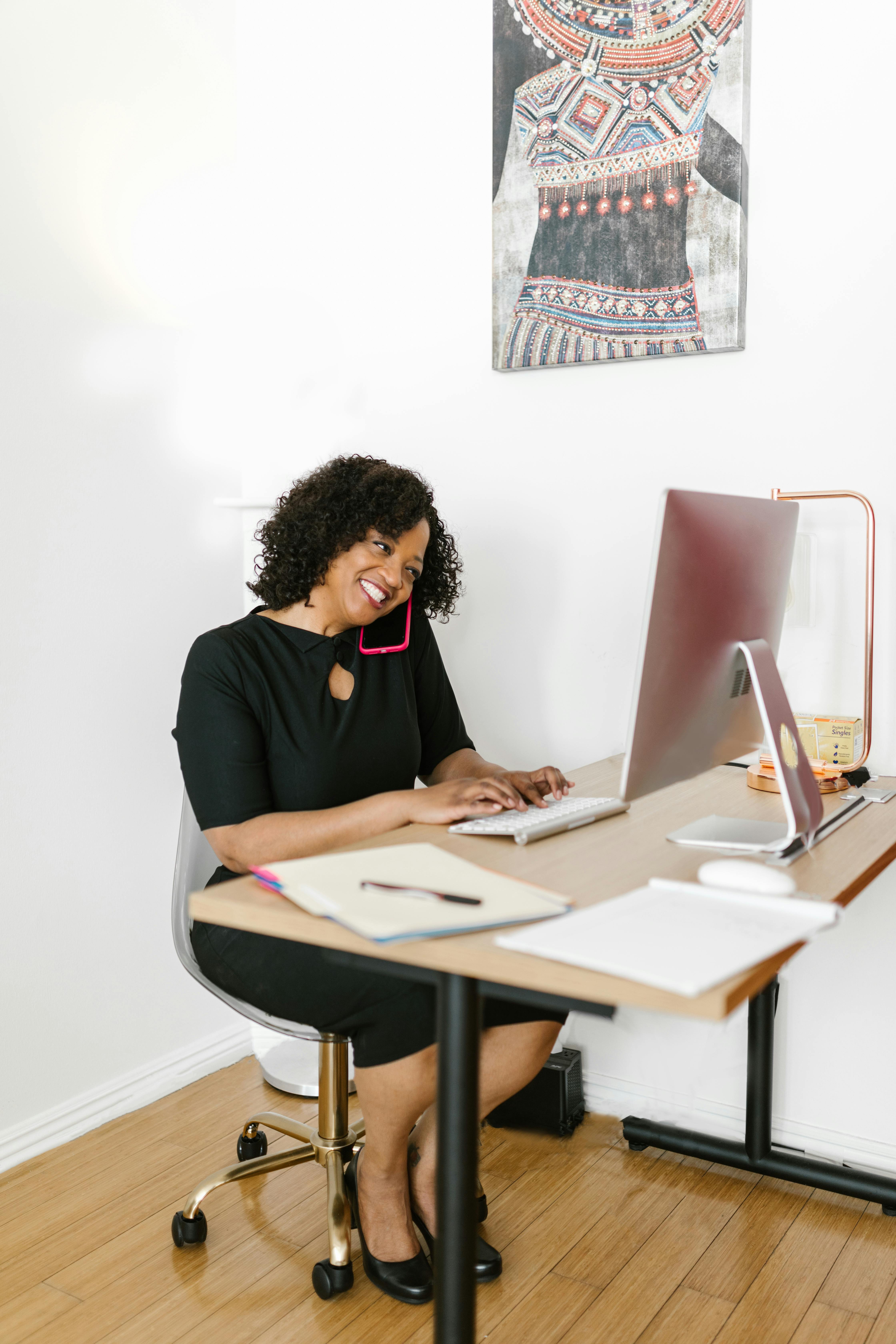 Woman Talking on Smartphone while Typing on the Keyboard · Free Stock Photo