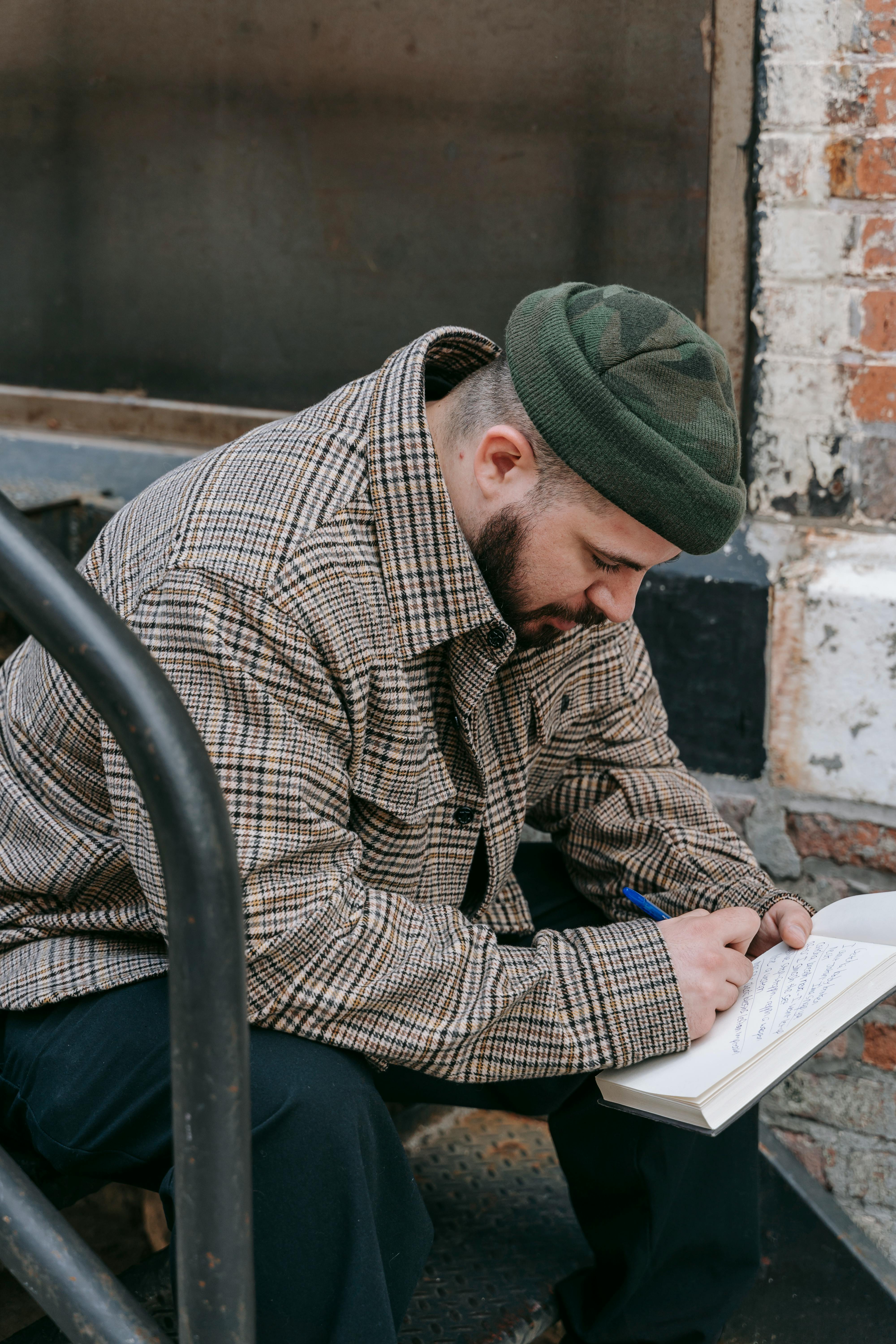 A Man Writing on a Notebook while Sitting on the Staircase · Free Stock ...
