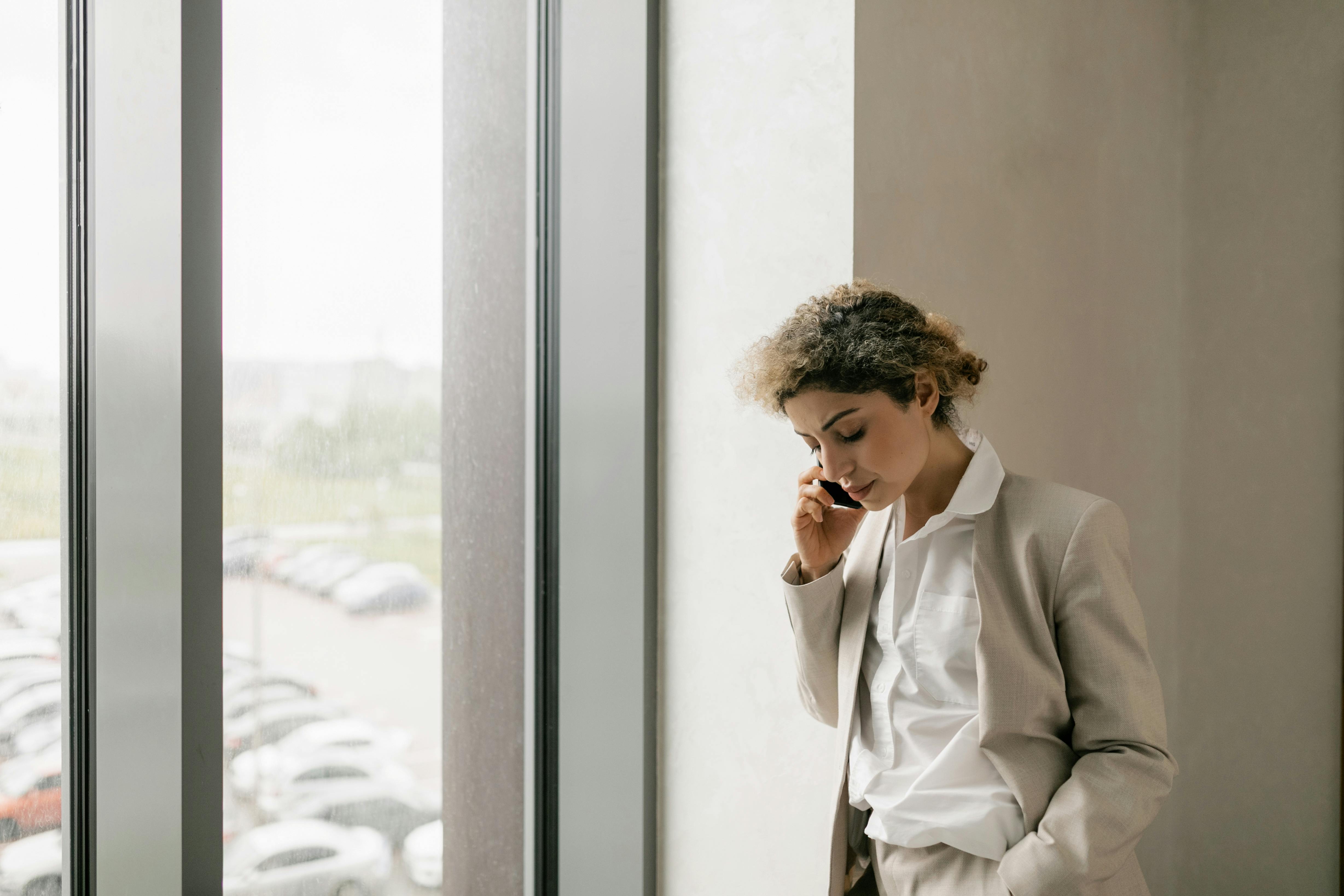 A Woman Standing Beside Window while Talking on the Phone · Free Stock ...