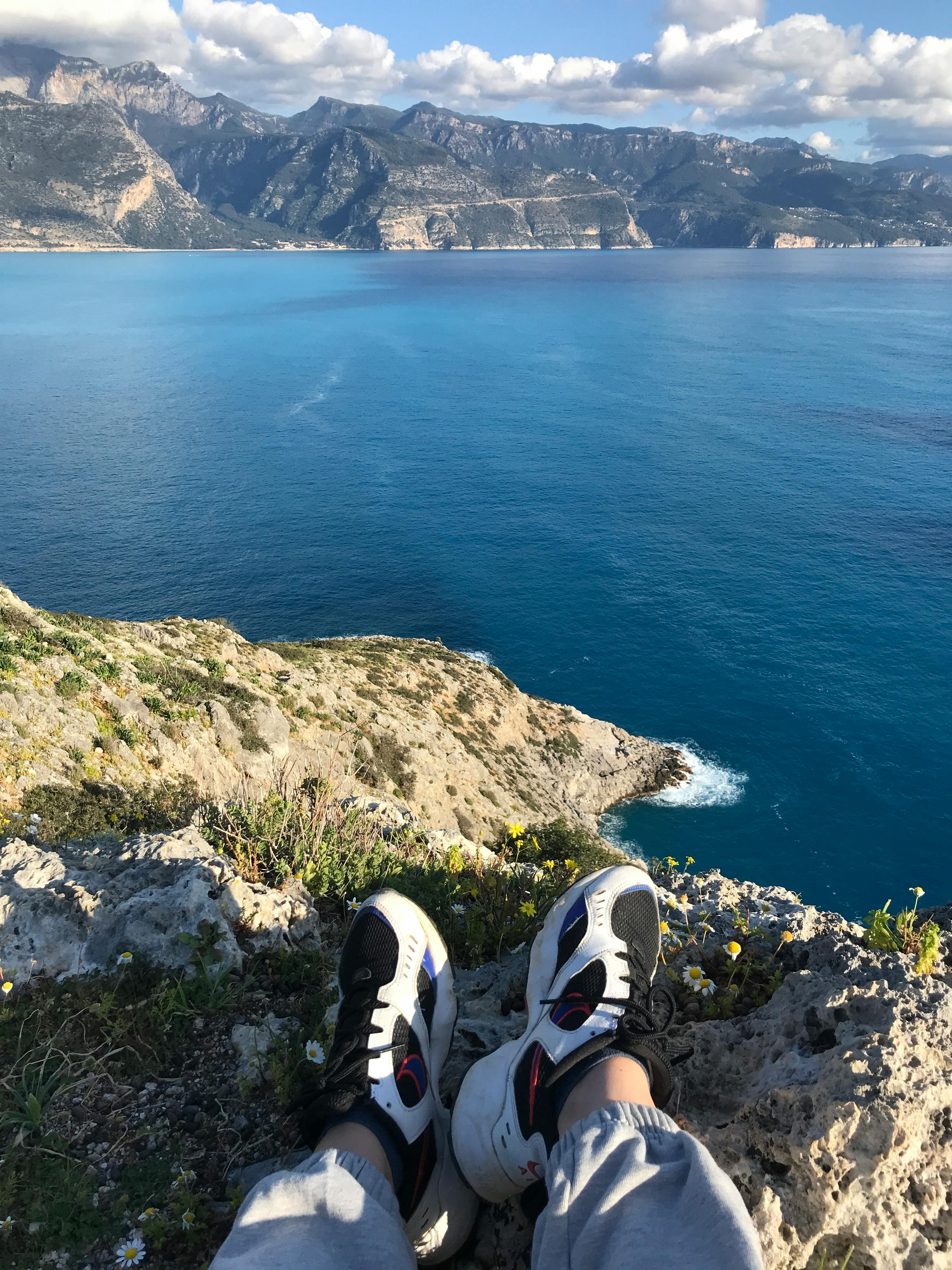 A Person Sitting on a Cliff in Fethiye/Mugla, Turkey · Free Stock Photo