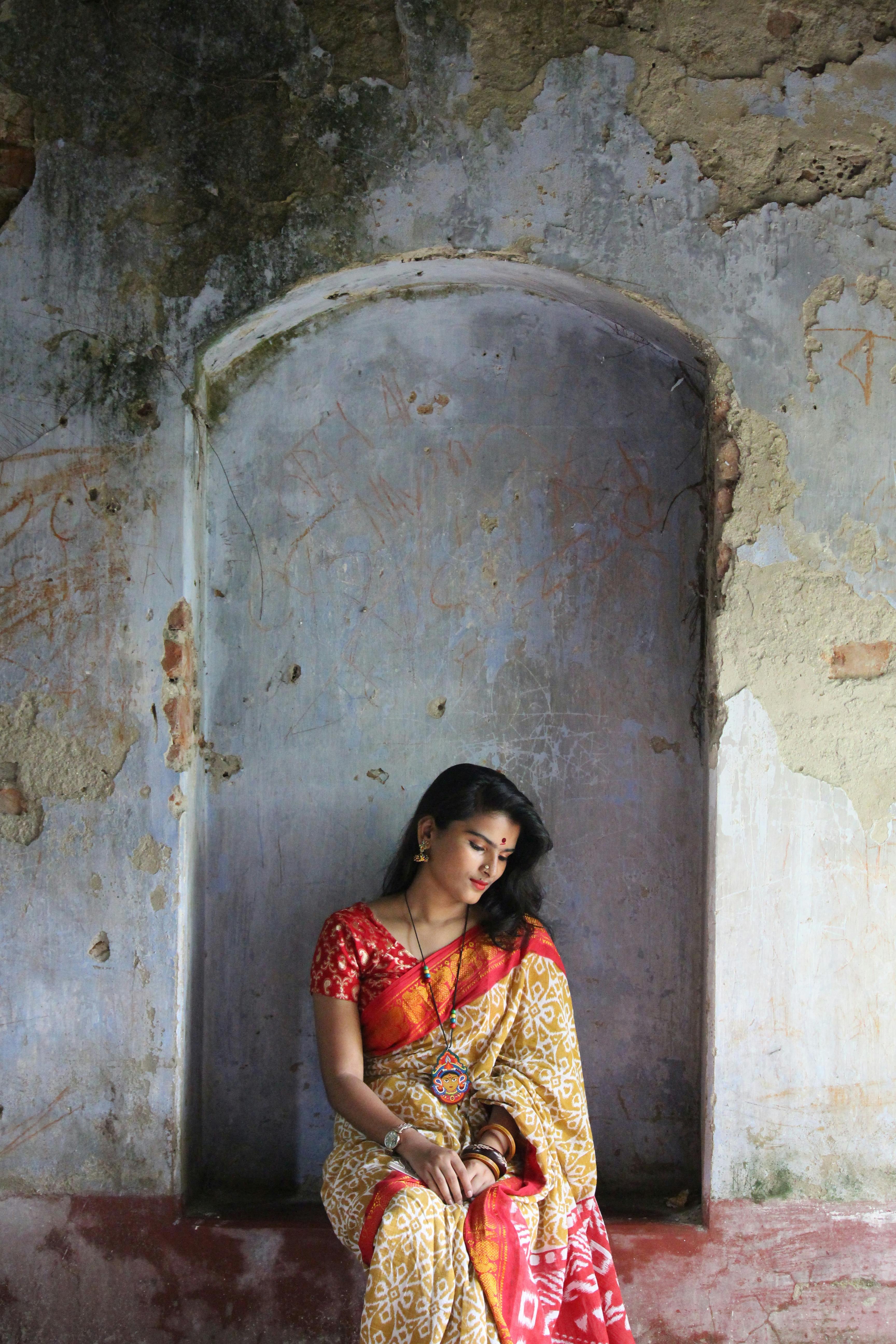 A Woman Wearing Saree Sitting on a Wall Recess · Free Stock Photo