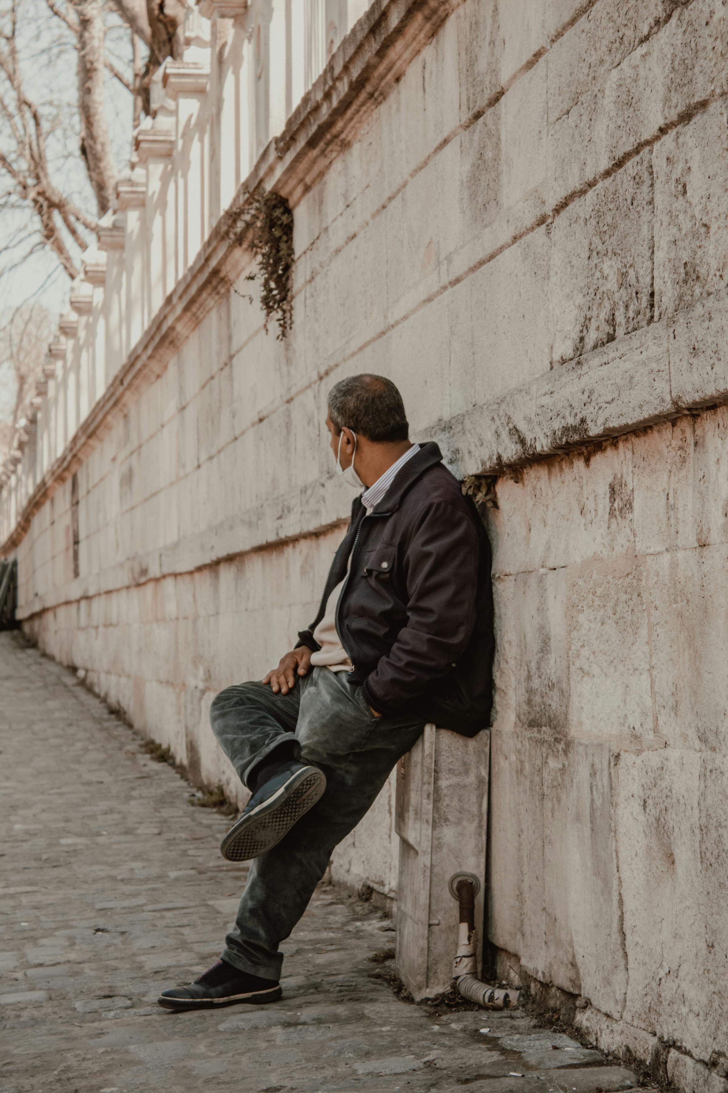 Man Leaning Against Concrete Wall · Free Stock Photo