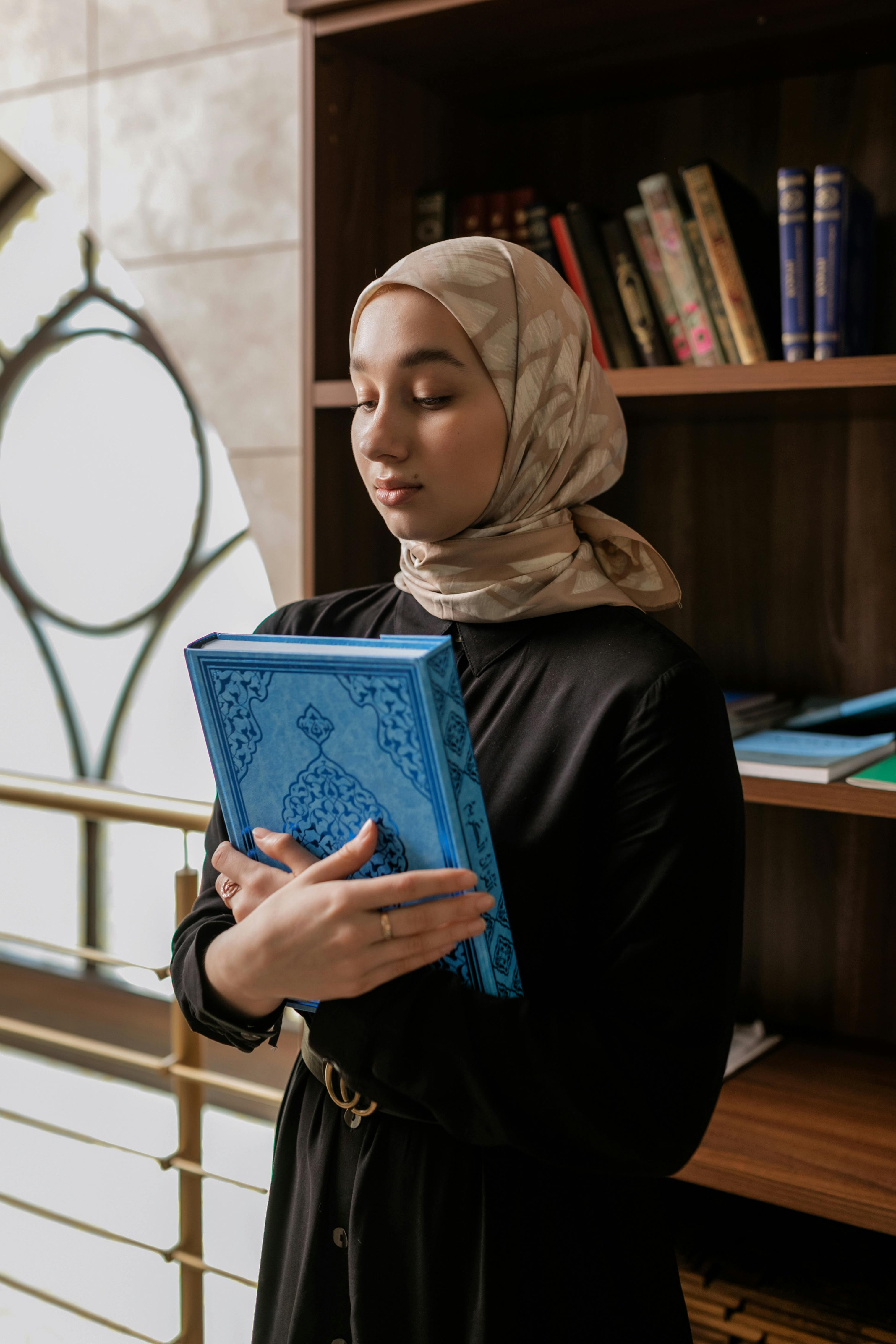 Woman in Brown Hijab Holding a Blue Book · Free Stock Photo