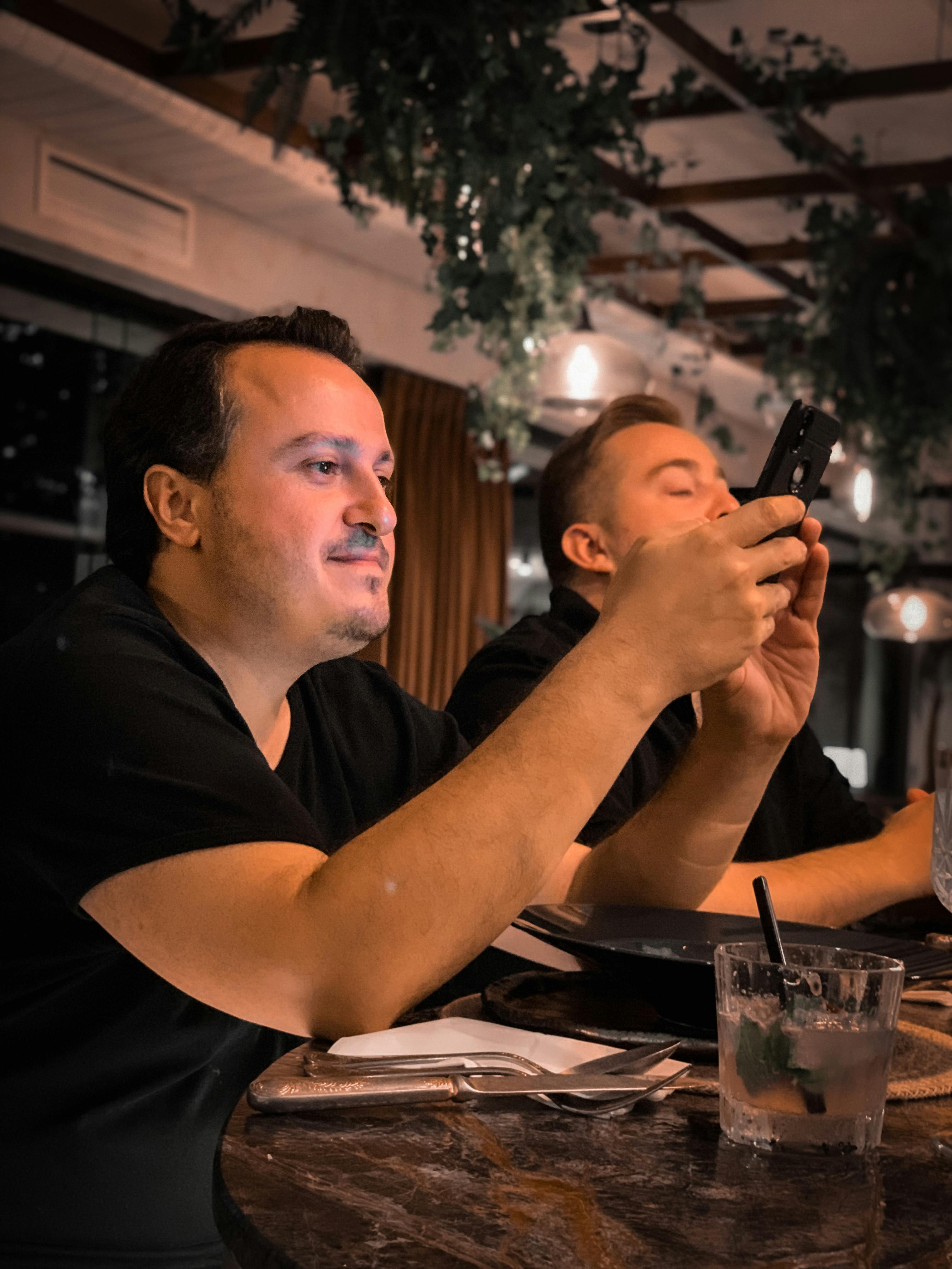 Men in Pub Checking their Smart Phones · Free Stock Photo