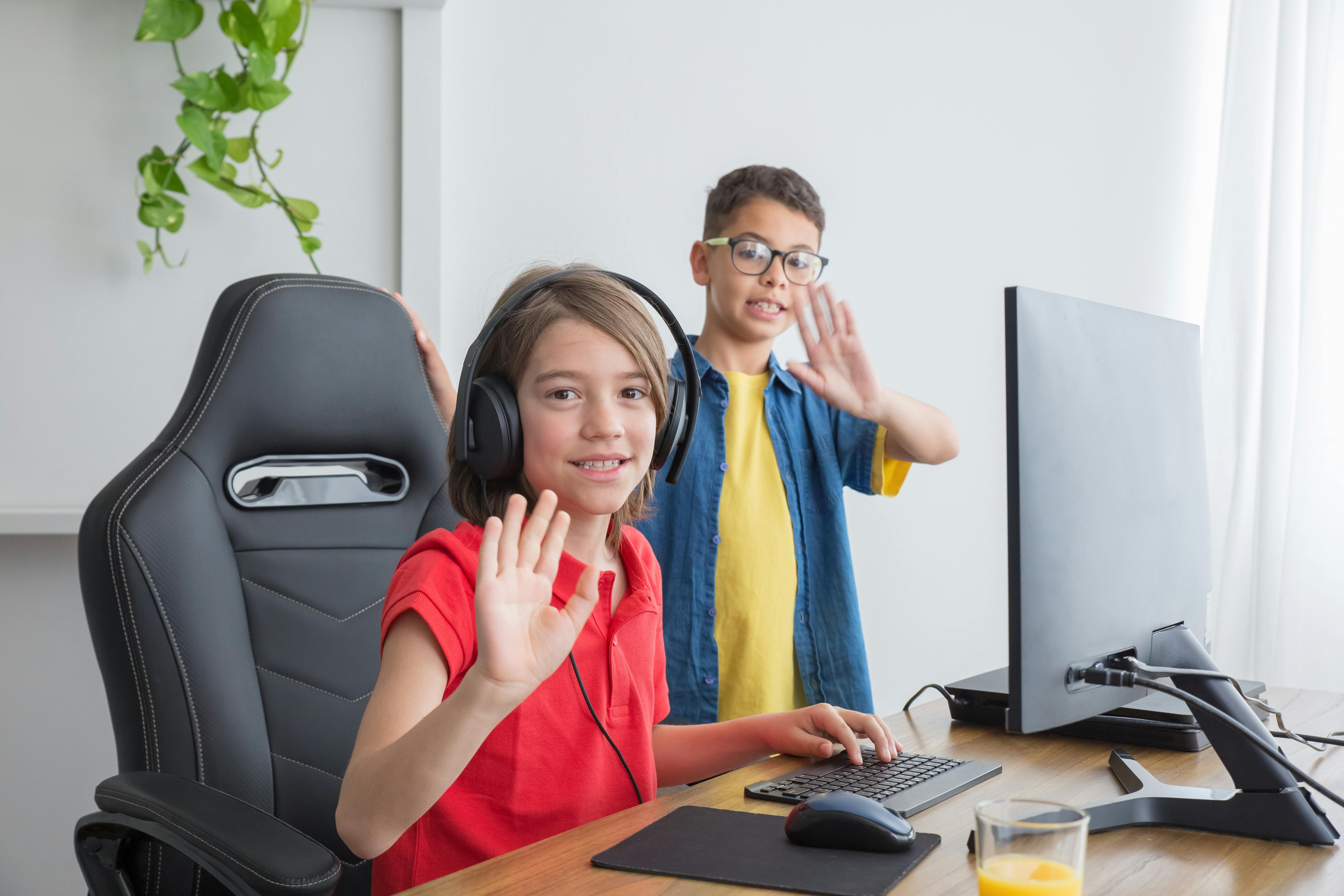 Two Children Sitting in front of a Computer and Waving at the Camera ...