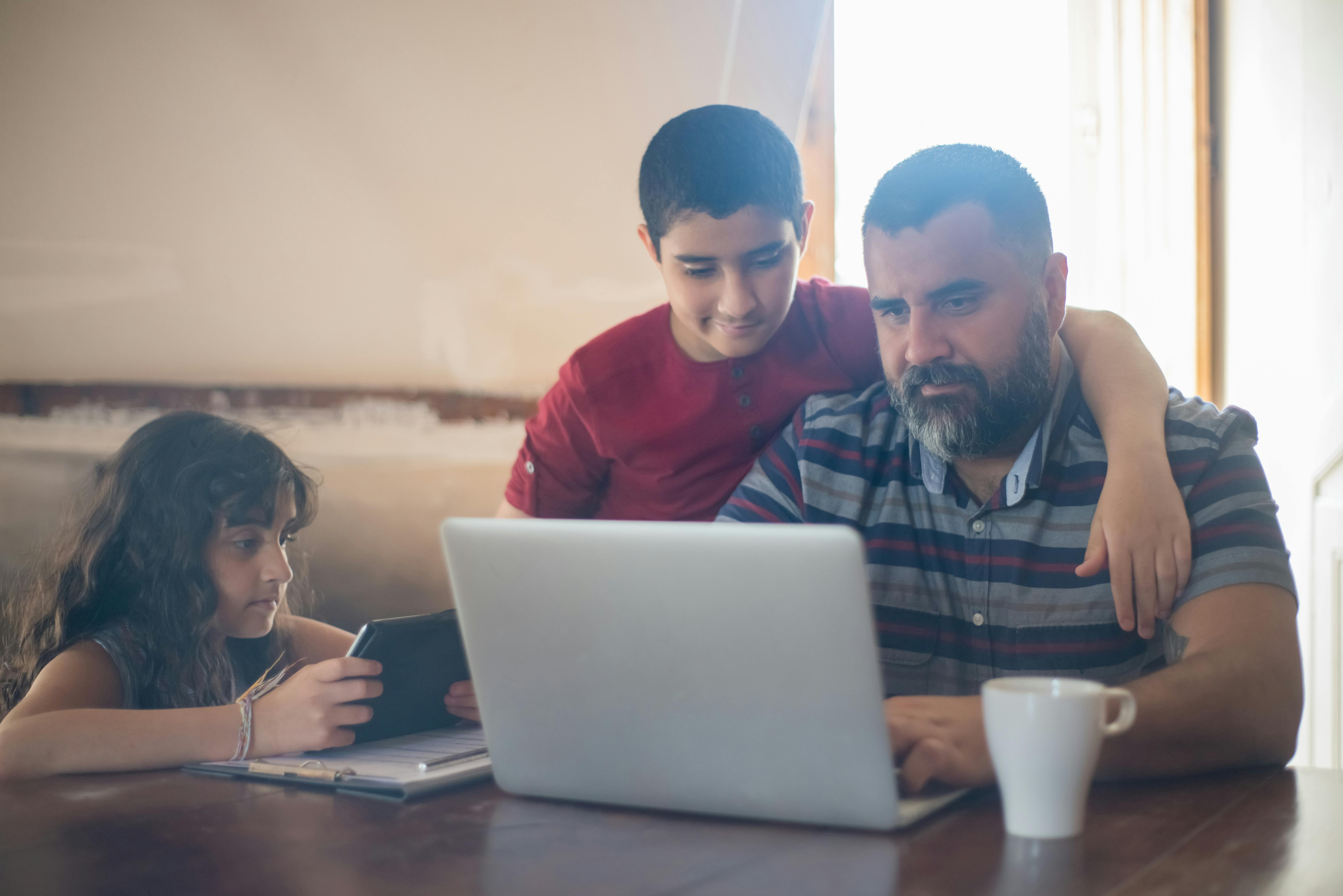 Three Children Looking at a Tablet Computer · Free Stock Photo