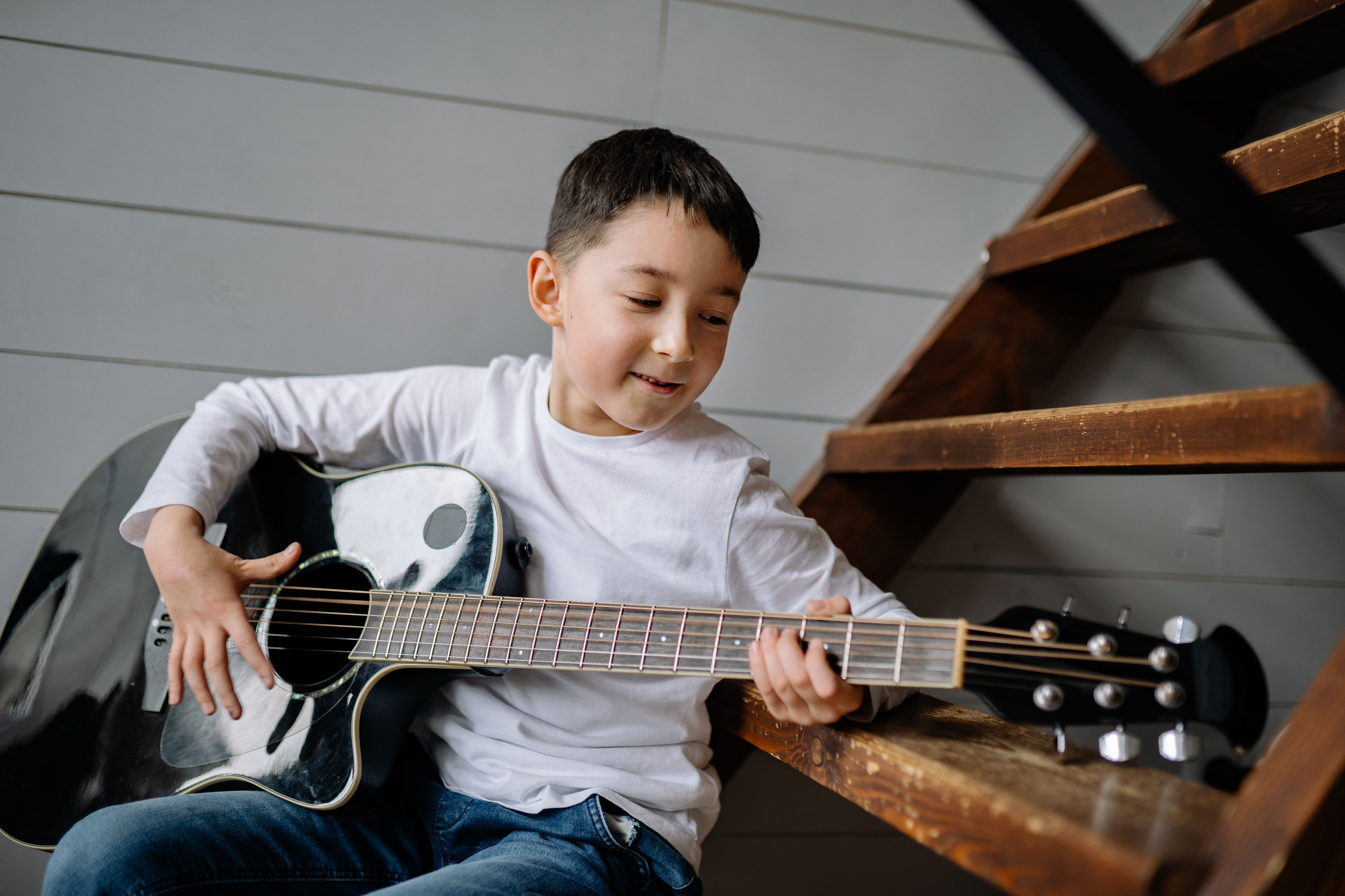 A Boy in White Long Sleeves Sitting beside an Acoustic Guitar · Free ...