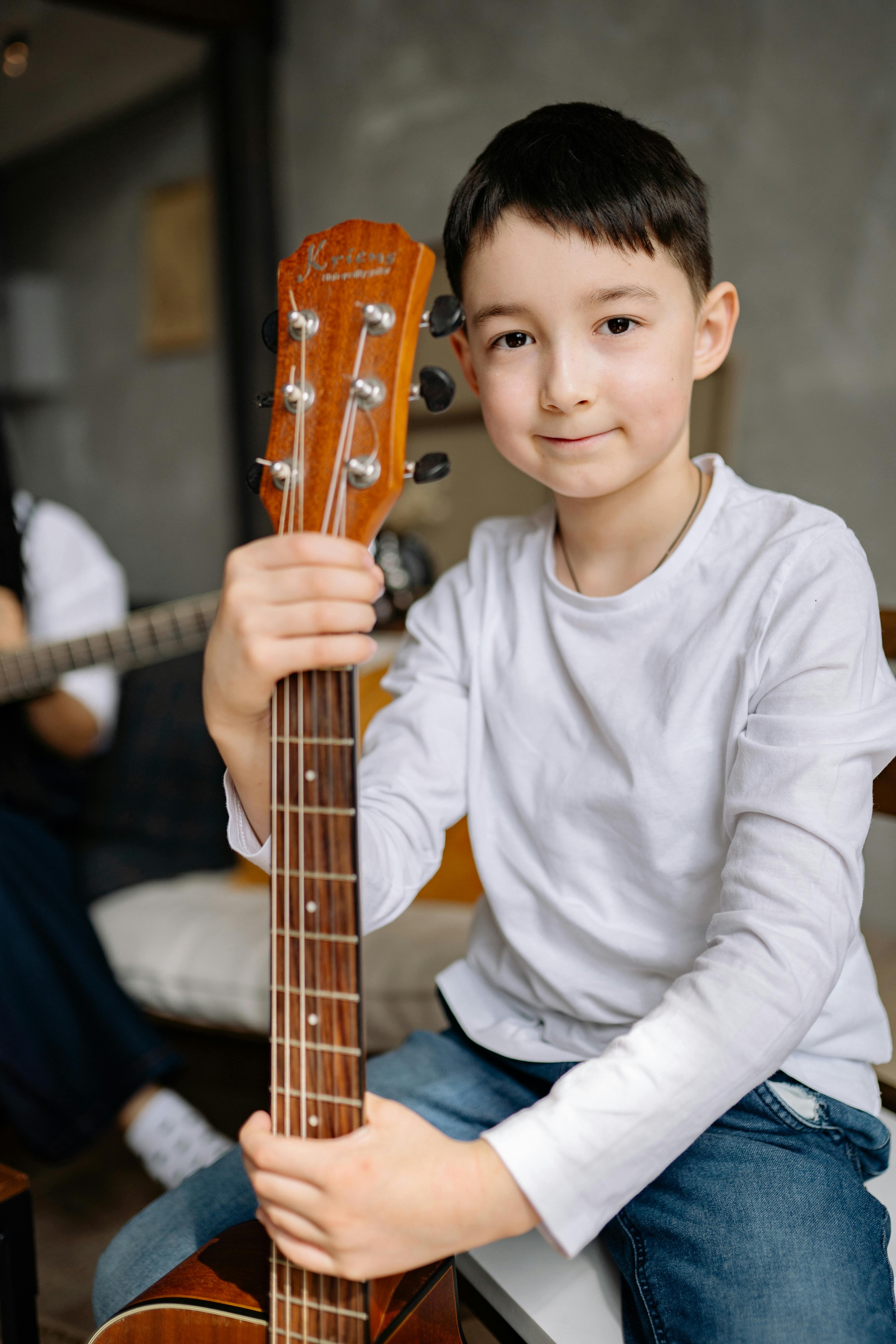 A Boy in White Long Sleeves Holding an Acoustic Guitar · Free Stock Photo