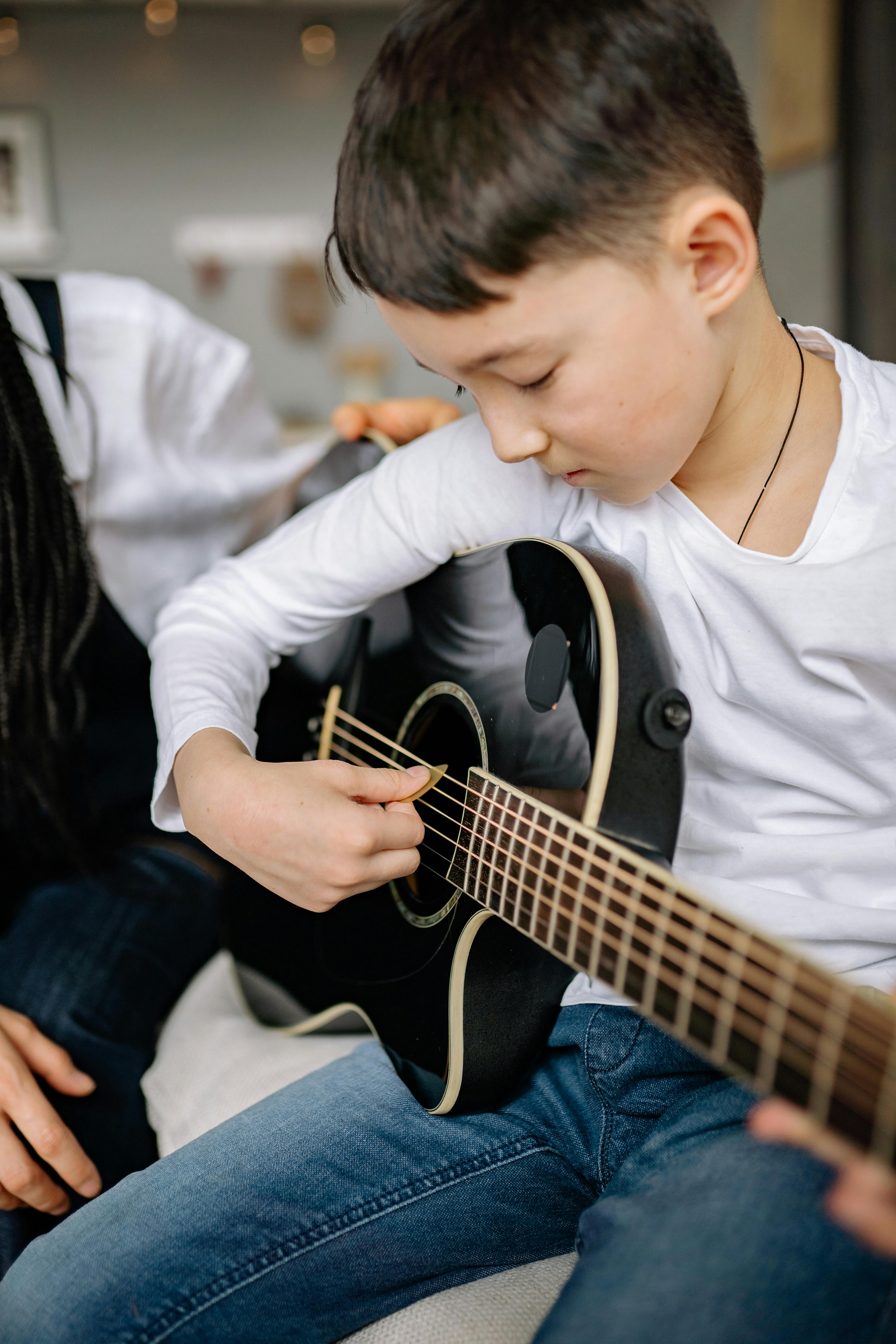Boy Strumming an Acoustic Guitar · Free Stock Photo