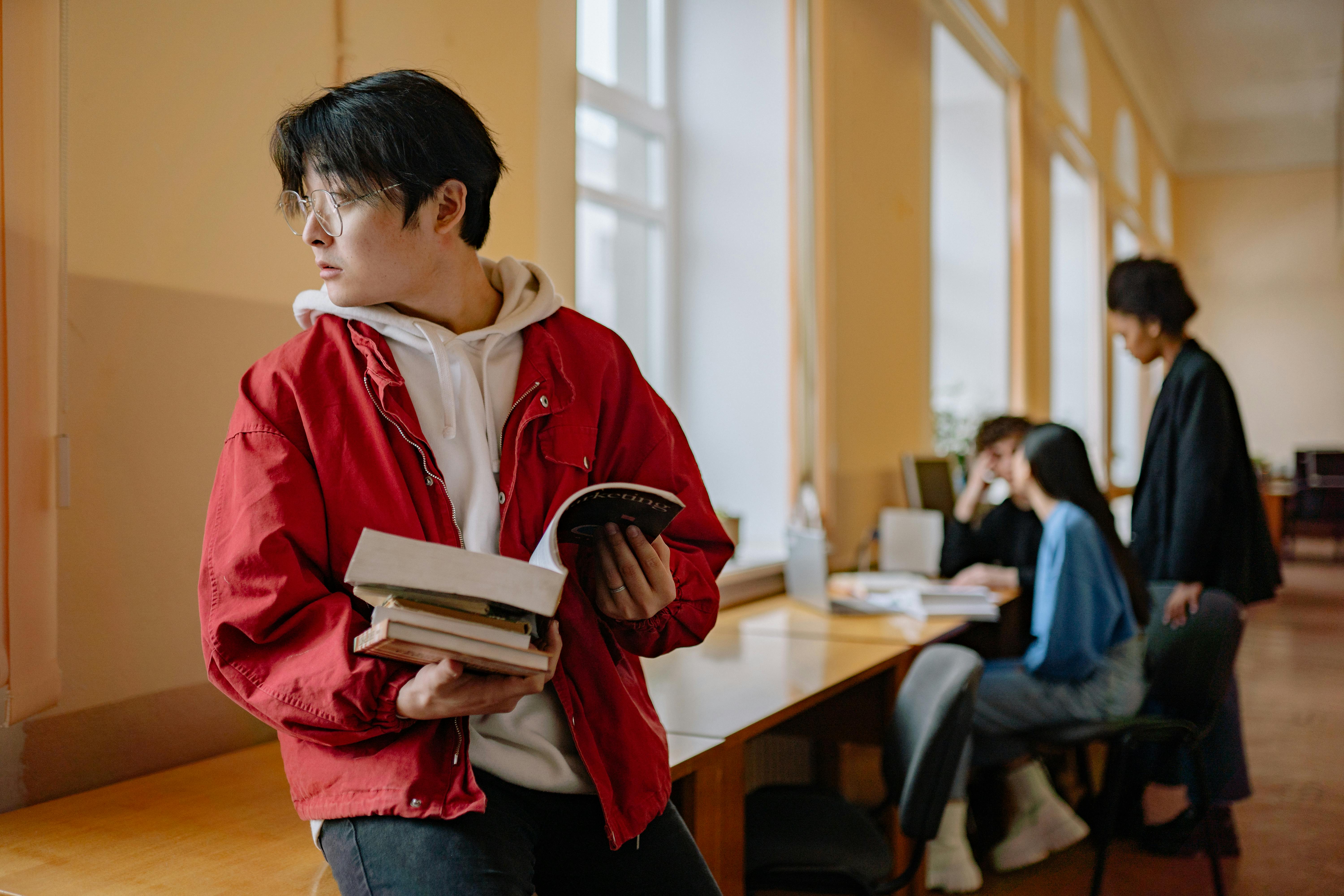 Man Sitting on Wooden Table while Holding Books in Library · Free Stock ...