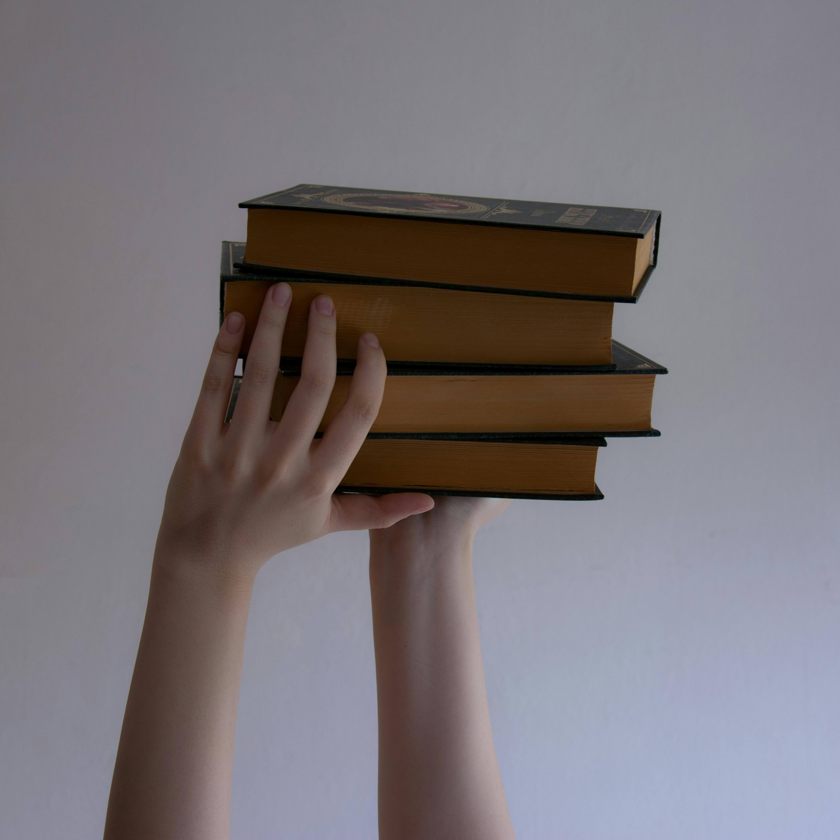 Pile Of Books On Hand · Free Stock Photo