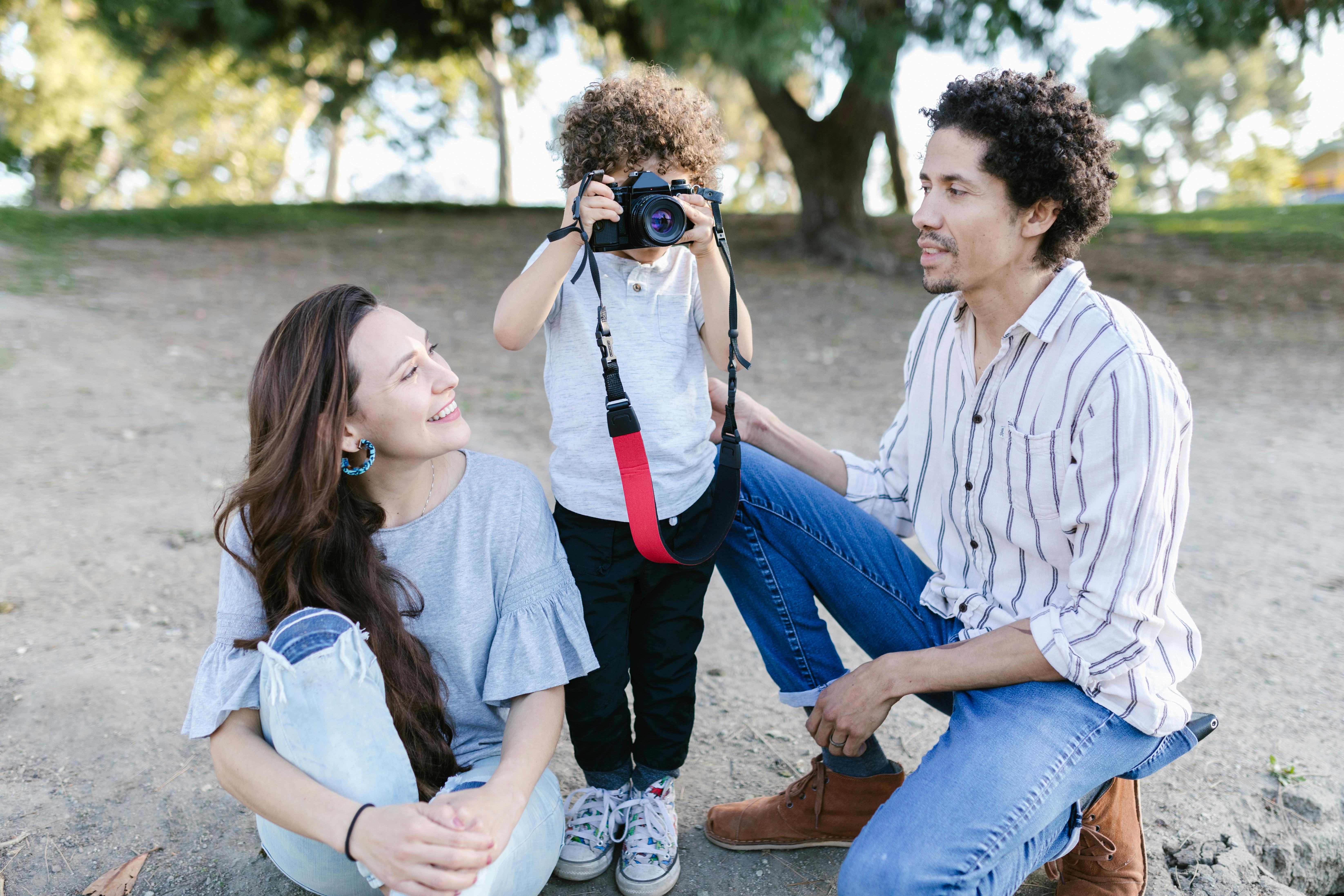 Photo of a Kid Using a Camera Near His Parents · Free Stock Photo