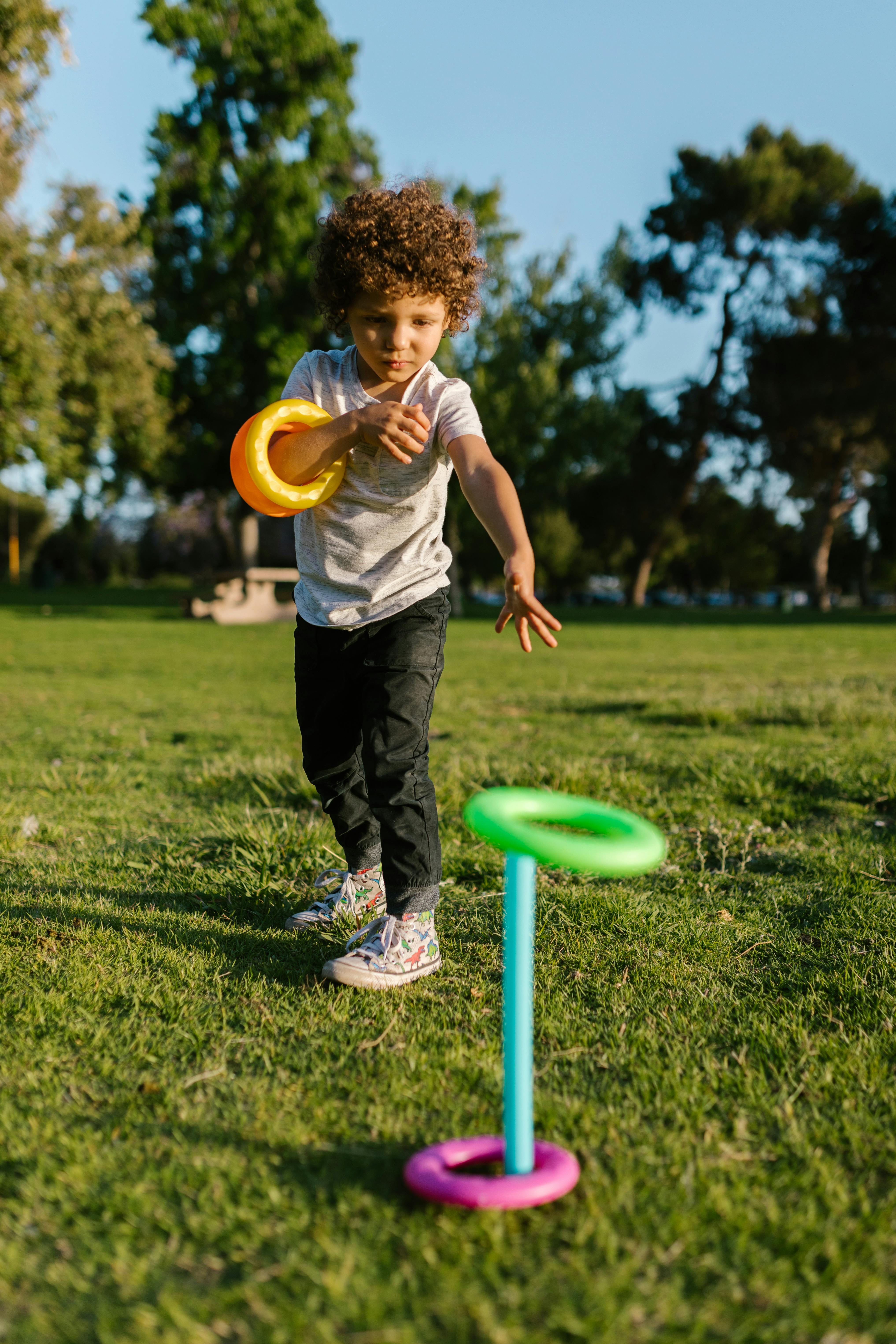 A Boy Playing Colorful Ring Toys in the Park · Free Stock Photo