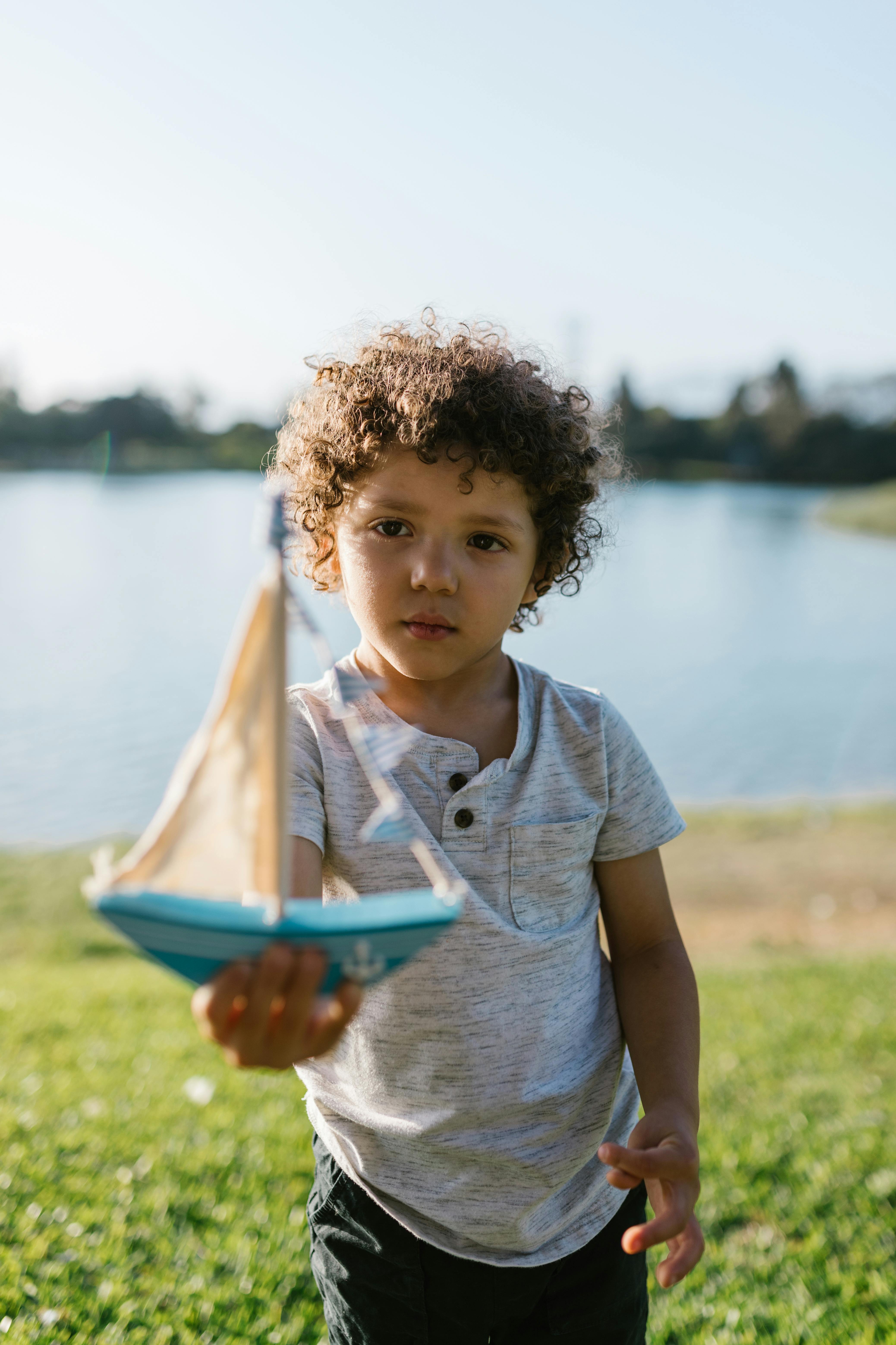 Photograph of a Boy Holding a Toy Boat · Free Stock Photo