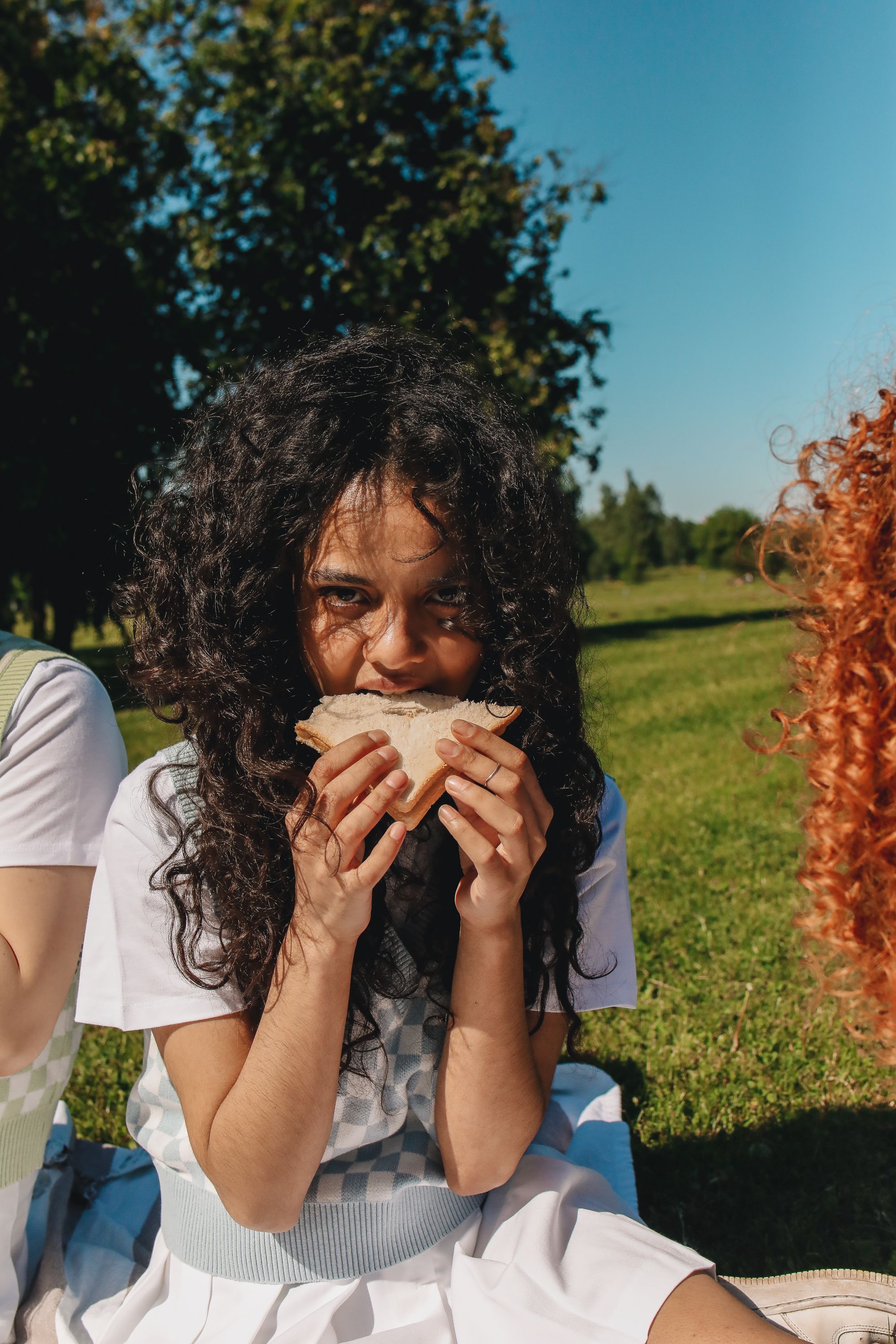 A Young Woman Eating a Sandwich at a Park · Free Stock Photo