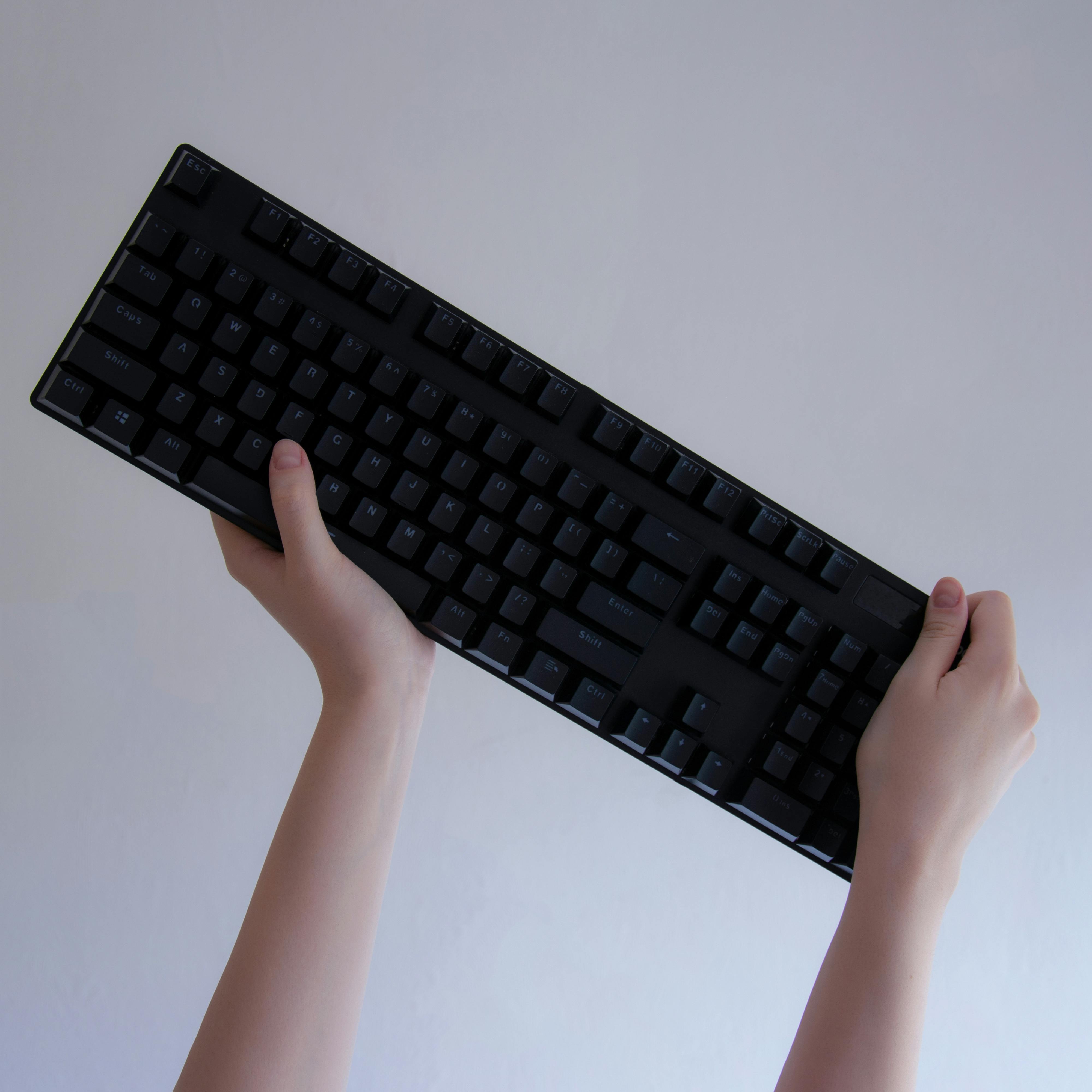 Photo of a Person's Hands Holding a Black Keyboard · Free Stock Photo