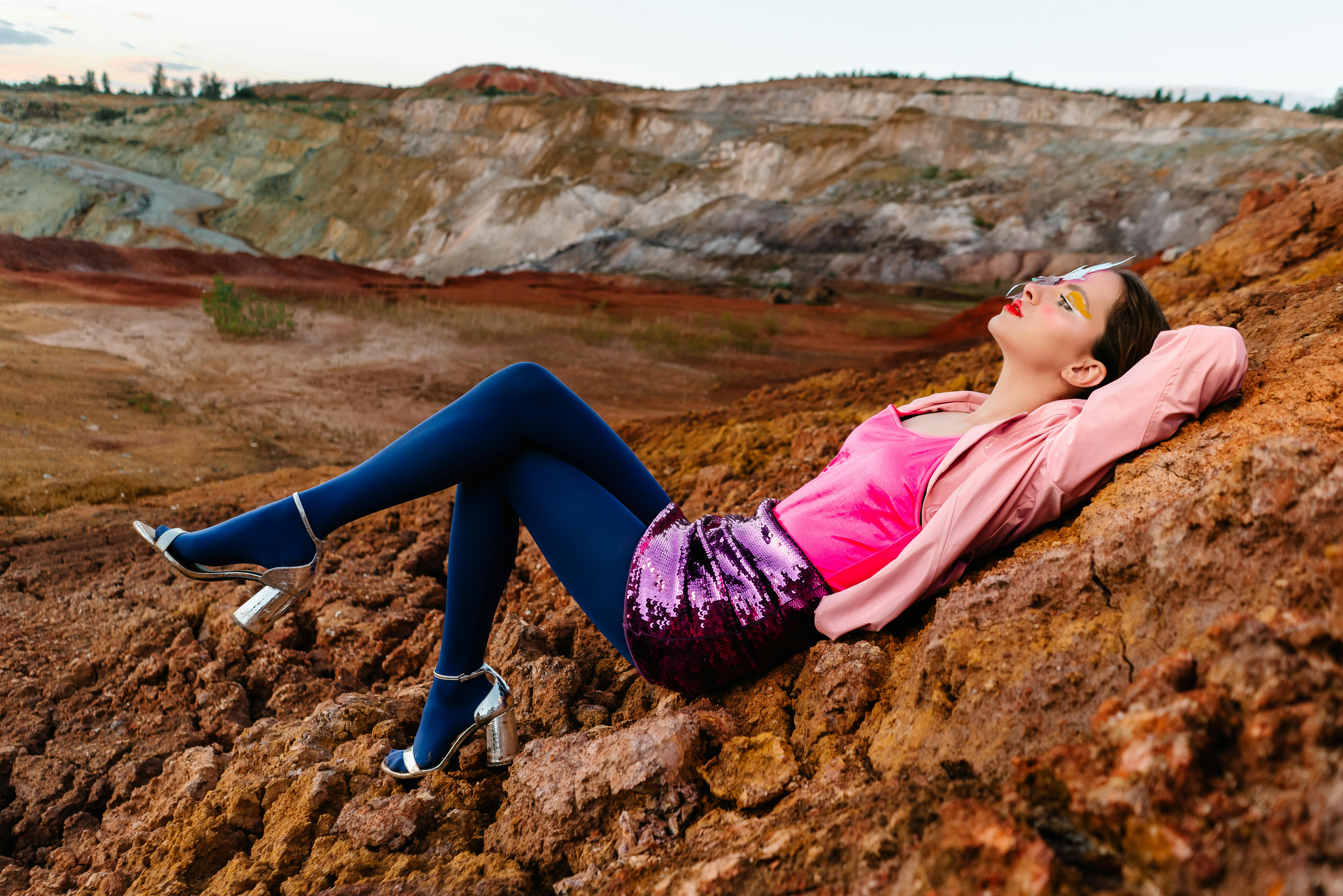 A Woman in a Pink Top and a Skirt Lying Down on Rocks · Free Stock Photo