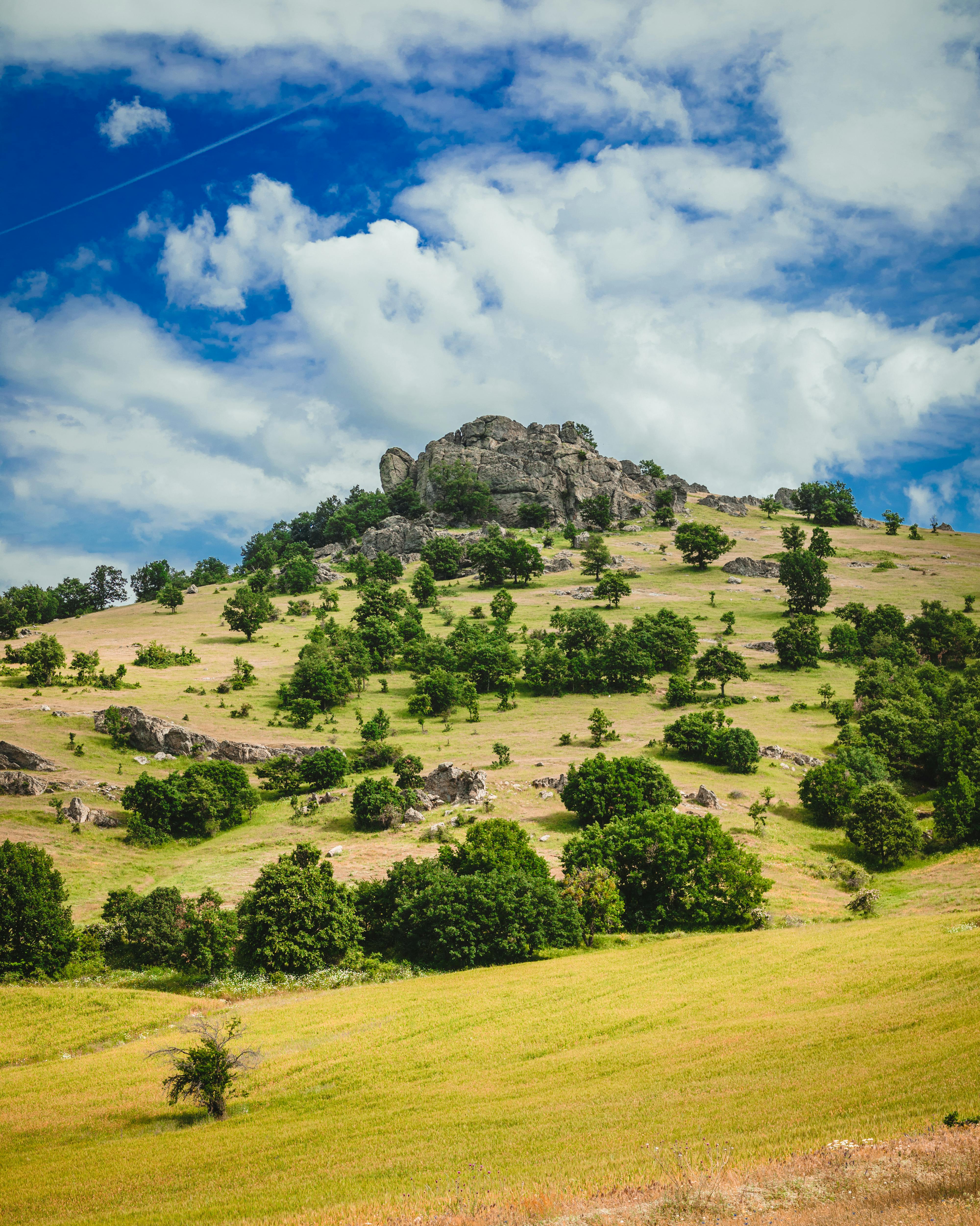 Green Hill with Rock against Blue Sky · Free Stock Photo