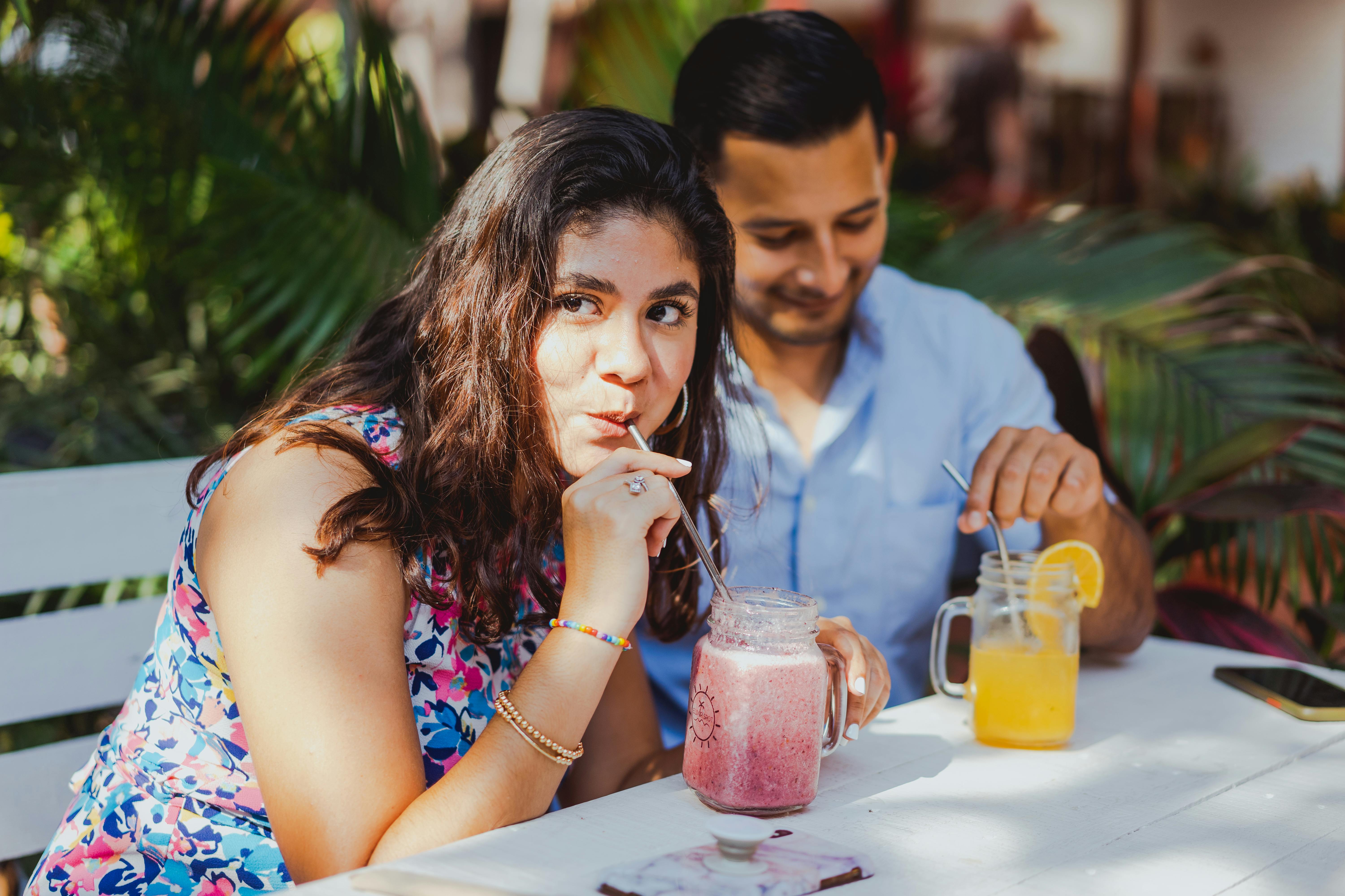 A Woman Sitting Beside a Man Sipping an Icee Drink from a Mason Jar ...