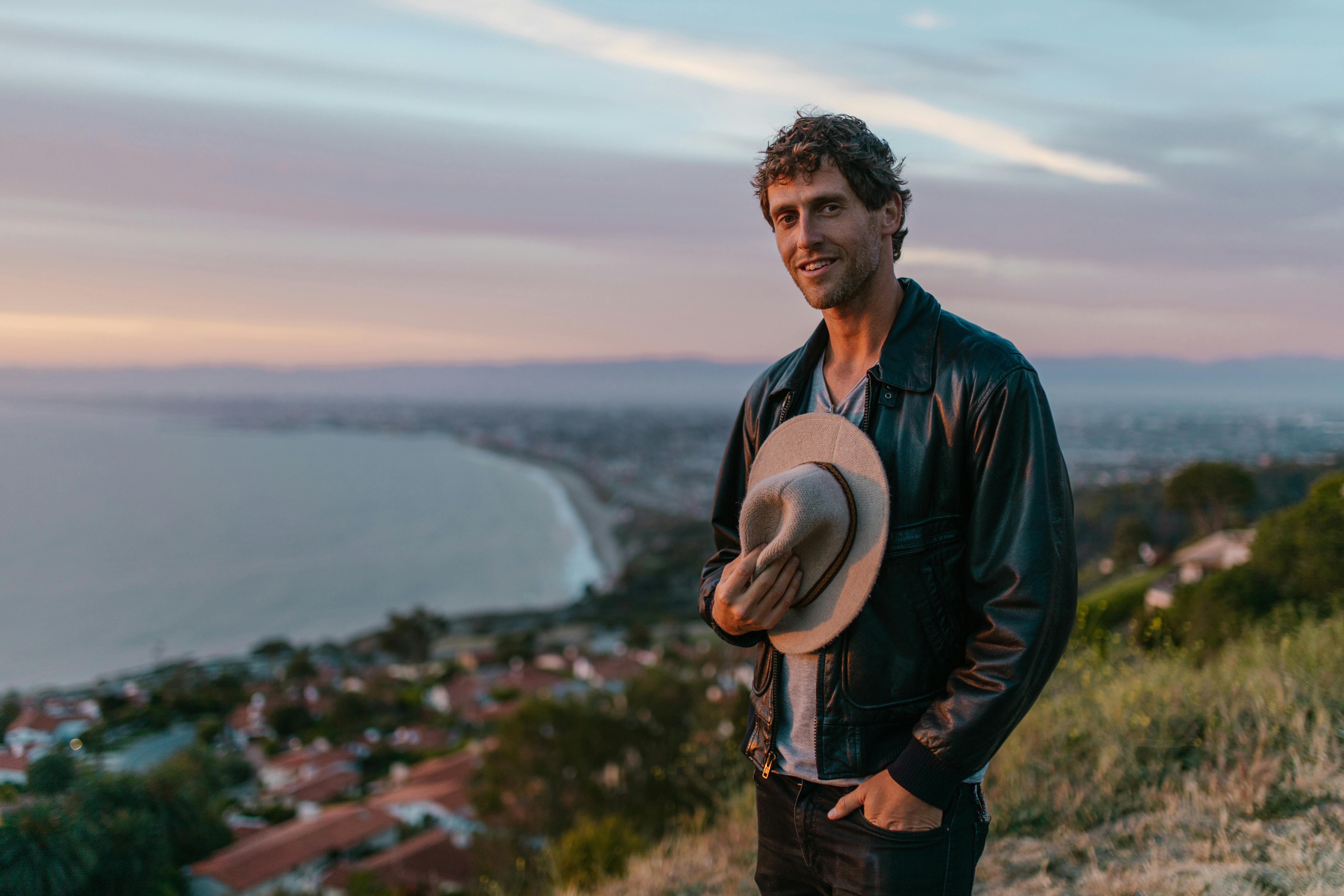 Person in Black Leather Jacket Holding a Hat · Free Stock Photo