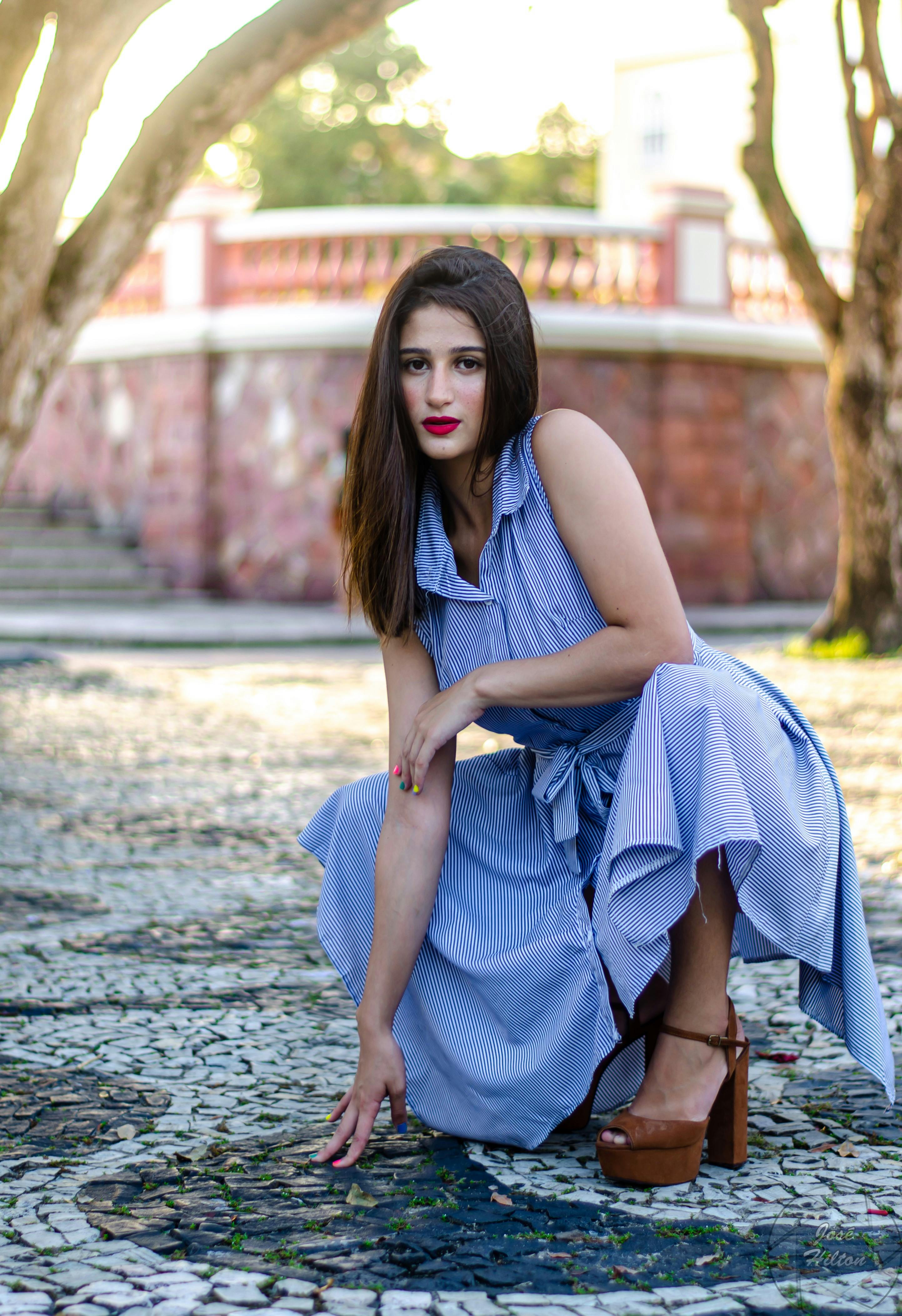 Woman Crouching on Ground Holding Blue Flare · Free Stock Photo
