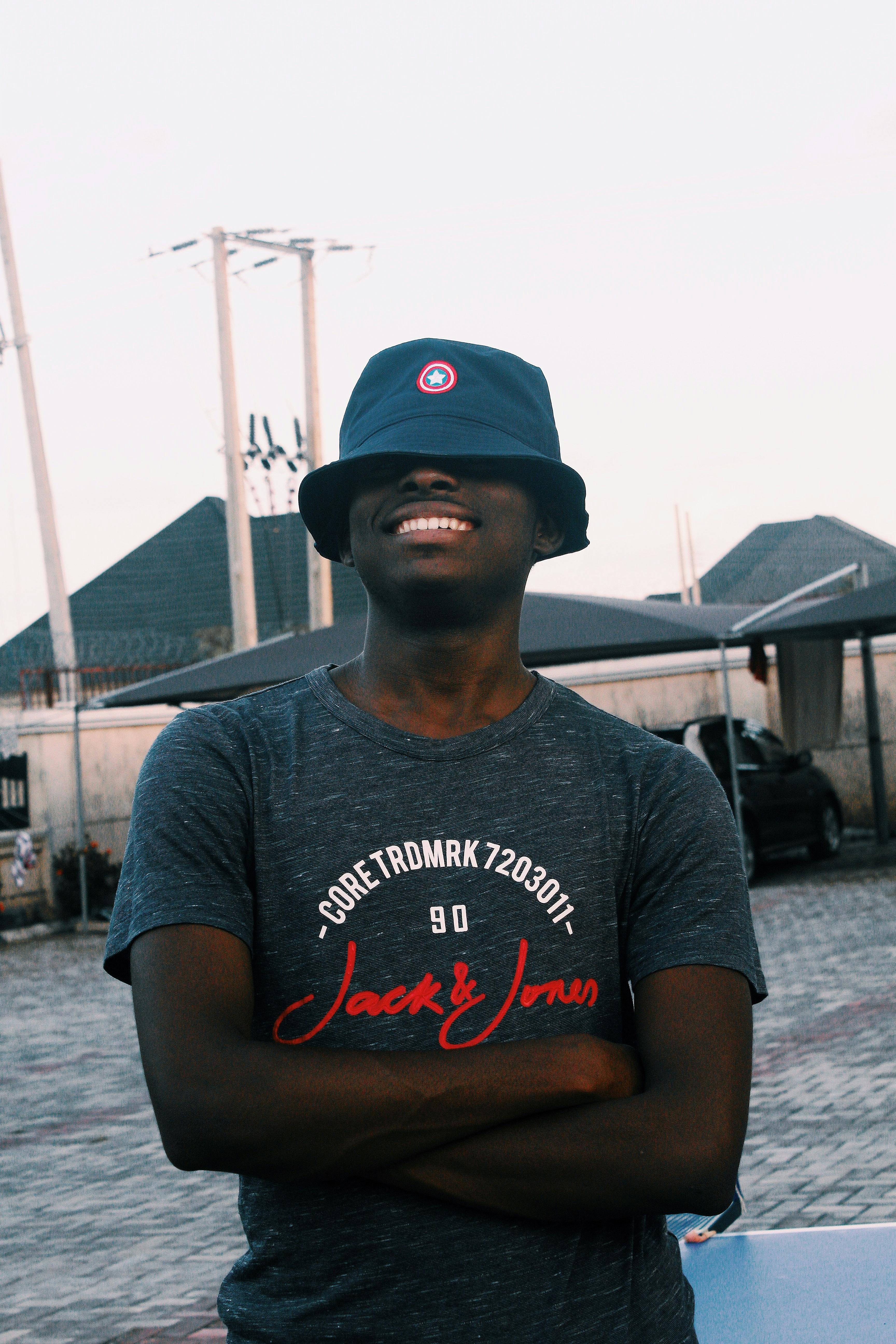 Smiling black man hiding face with hat · Free Stock Photo