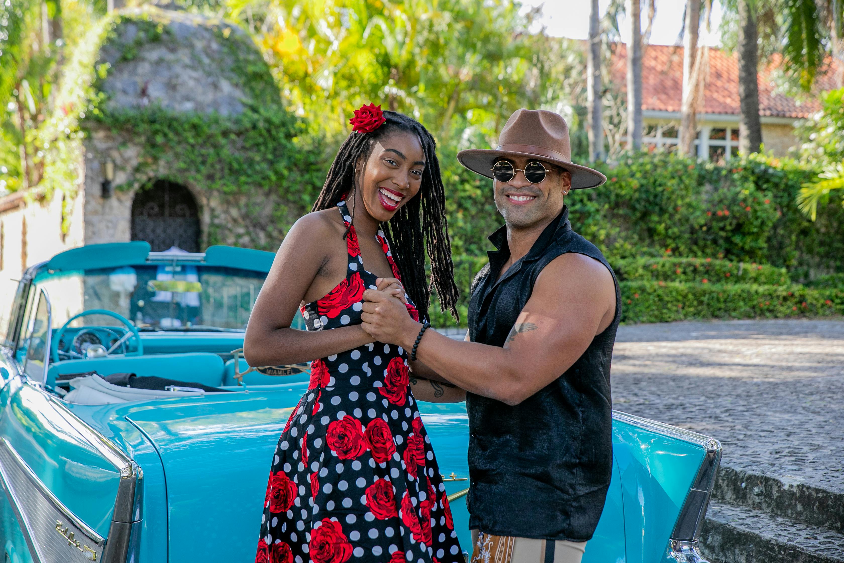 A Couple Smiling while Dancing Near a Blue Car · Free Stock Photo