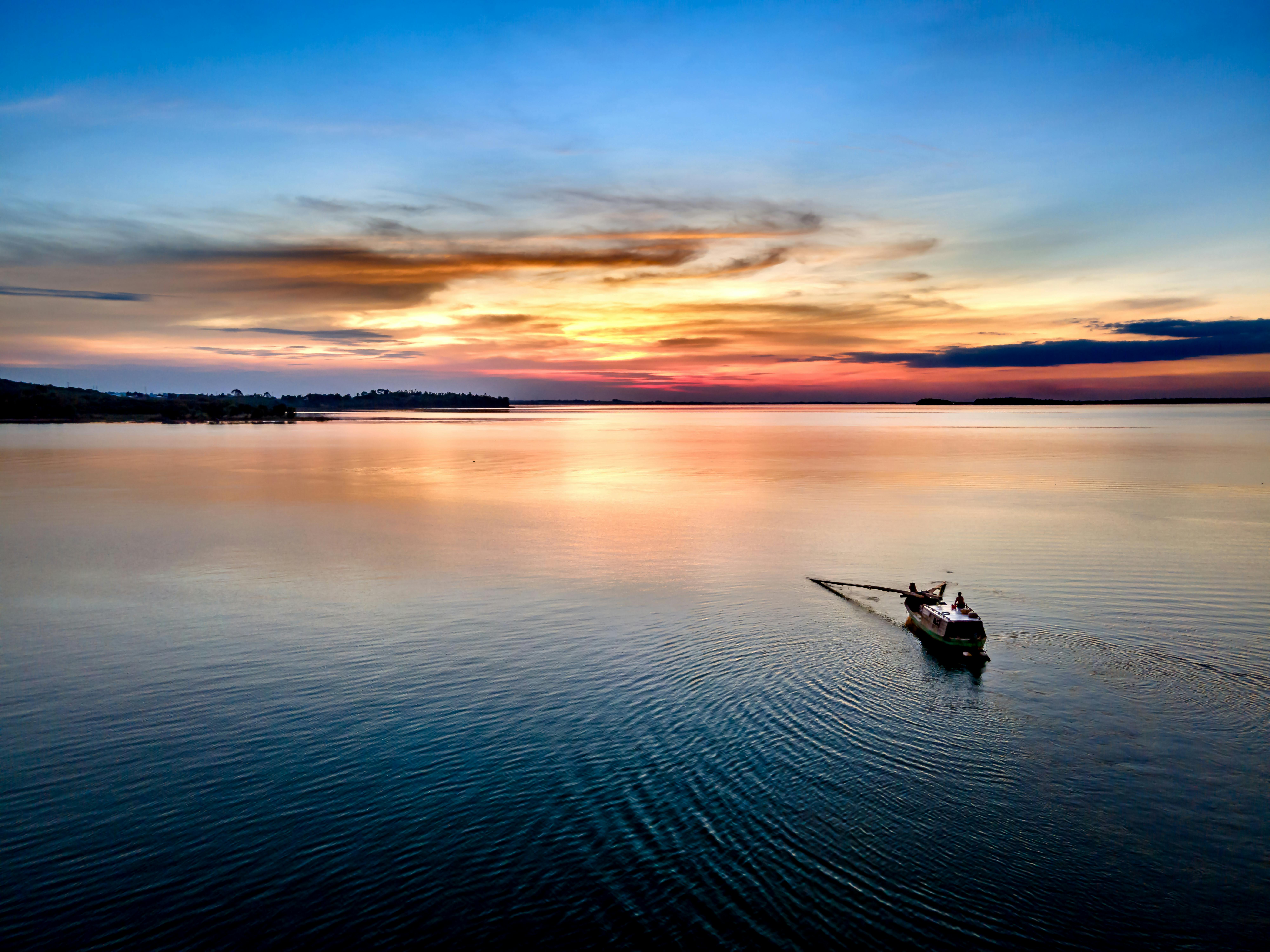 A Man Rowing A Small Boat With a Sail · Free Stock Photo
