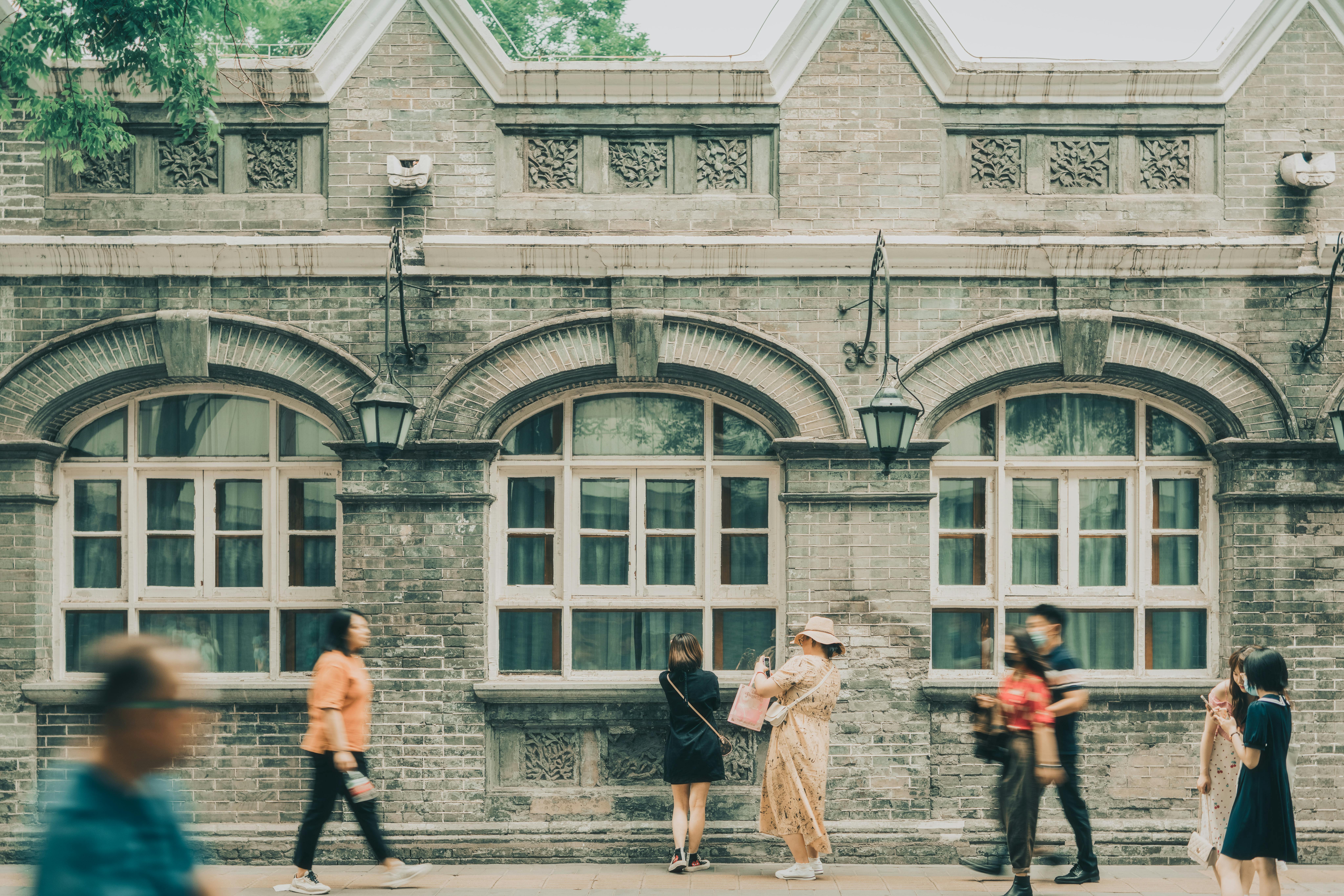 People Standing and Walking Beside a Concrete Building with Glass ...