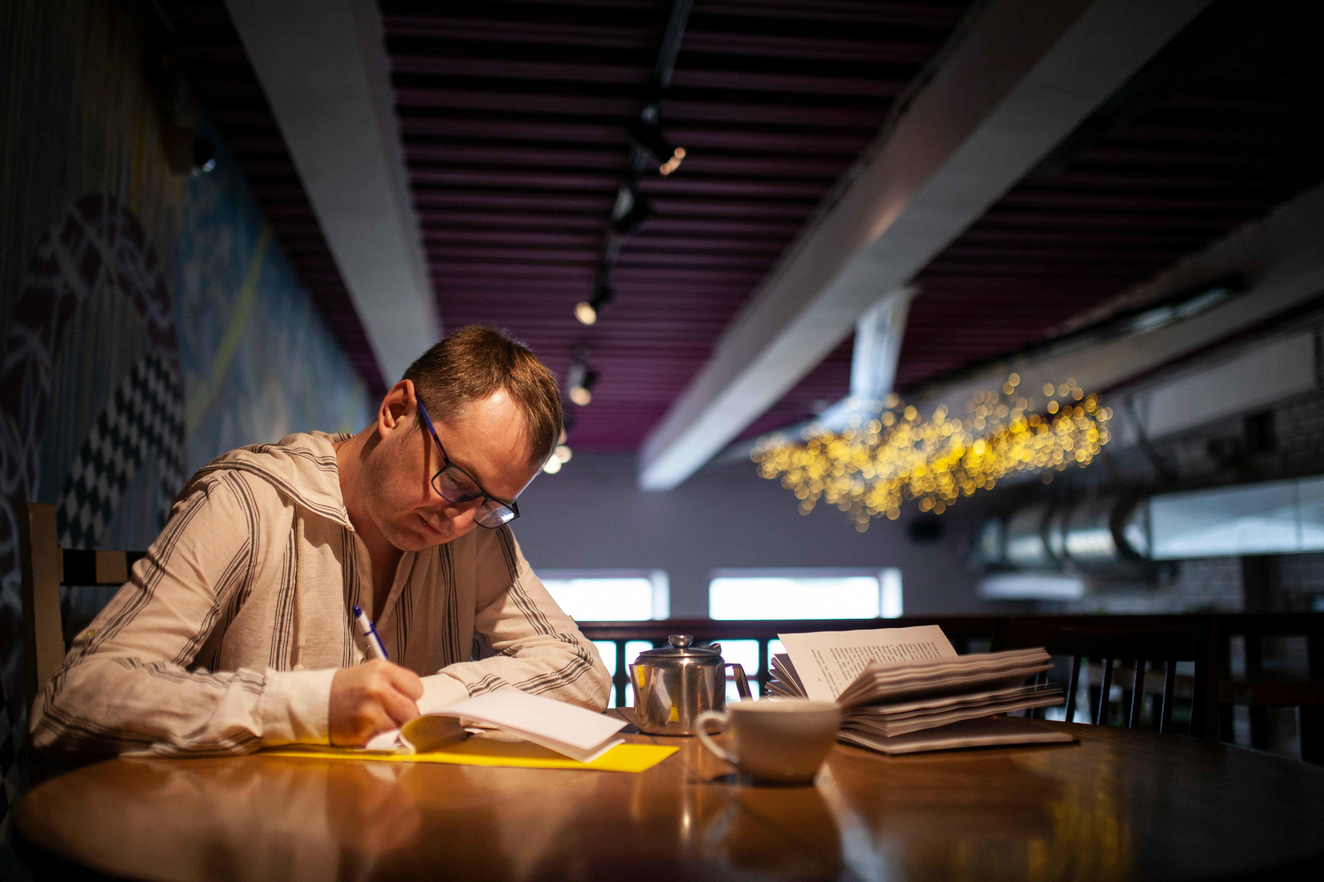 Man Sitting and Writing · Free Stock Photo