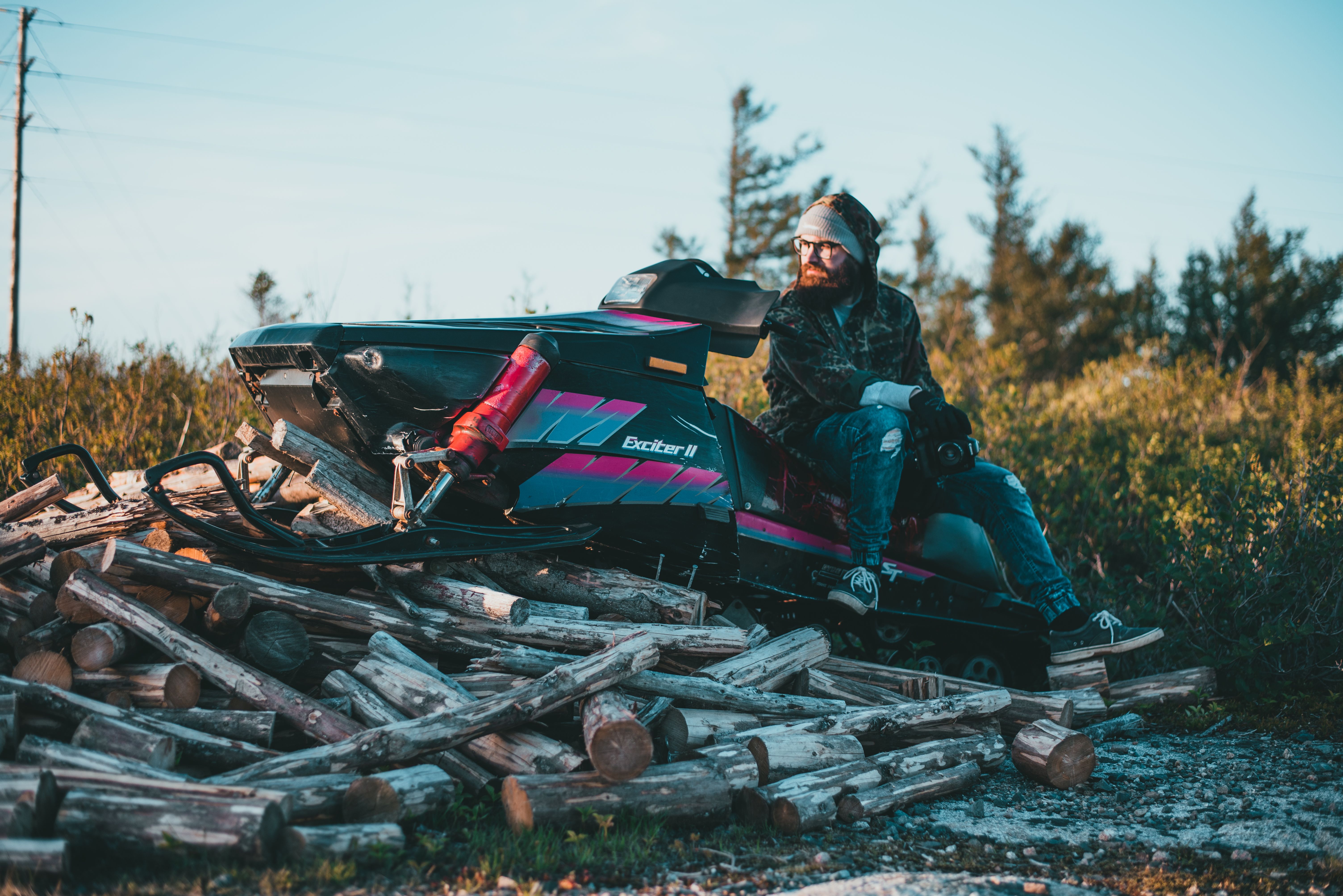 Man Sitting on a Snowmobile on a Pile o Chopped Wood · Free Stock Photo