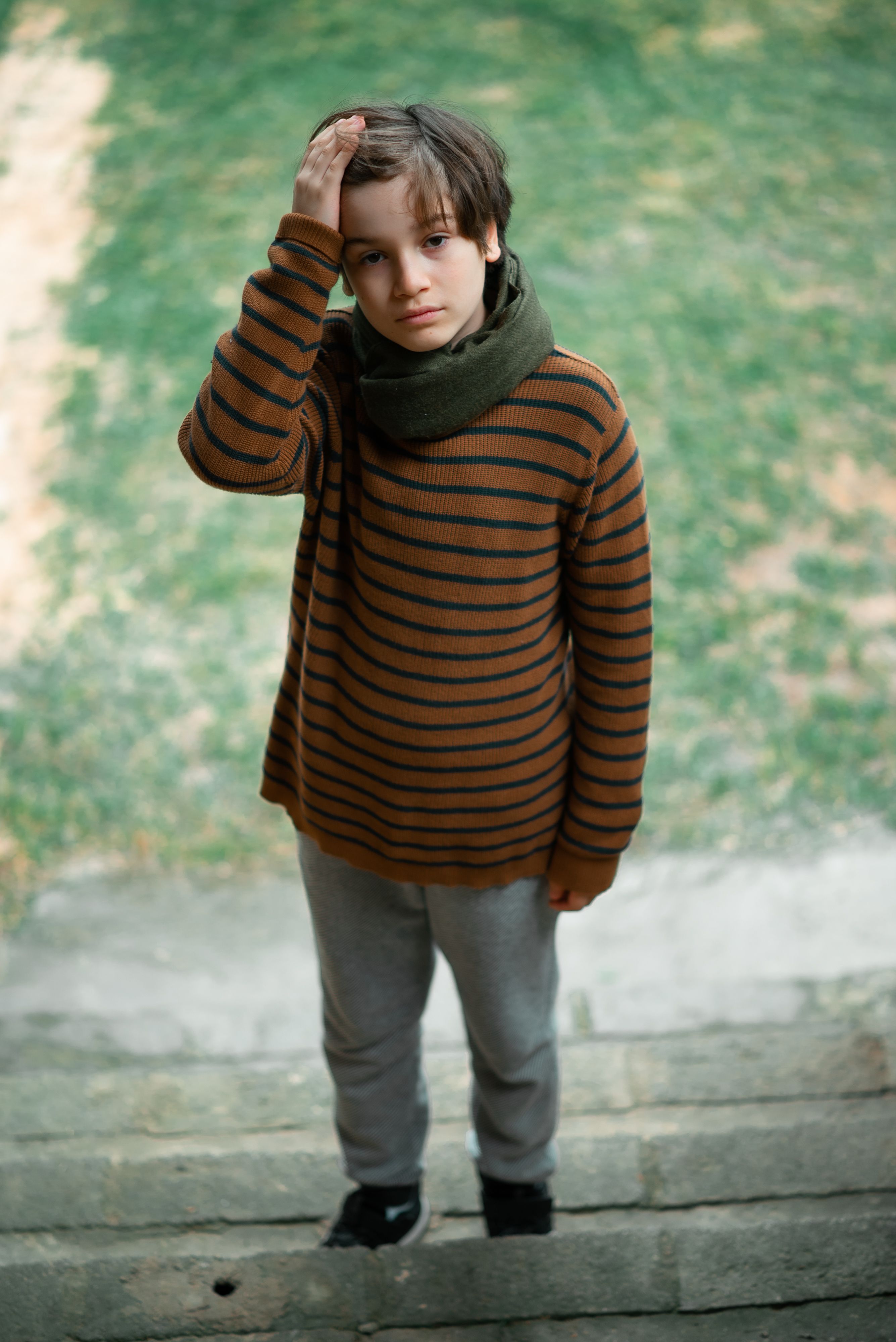 A Young Boy in Denim Jeans Sitting Near the White Wall · Free Stock Photo