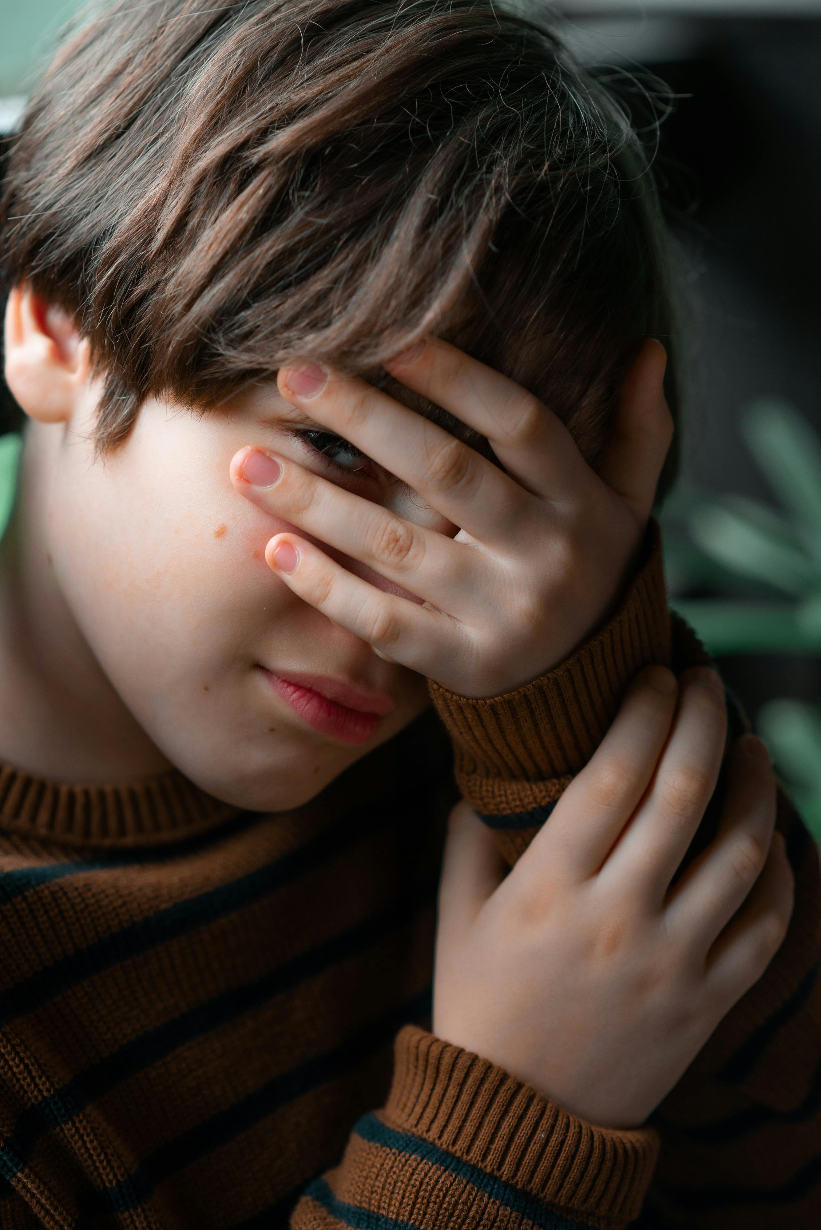 Kid in Striped Sweater with Hand on His Face · Free Stock Photo