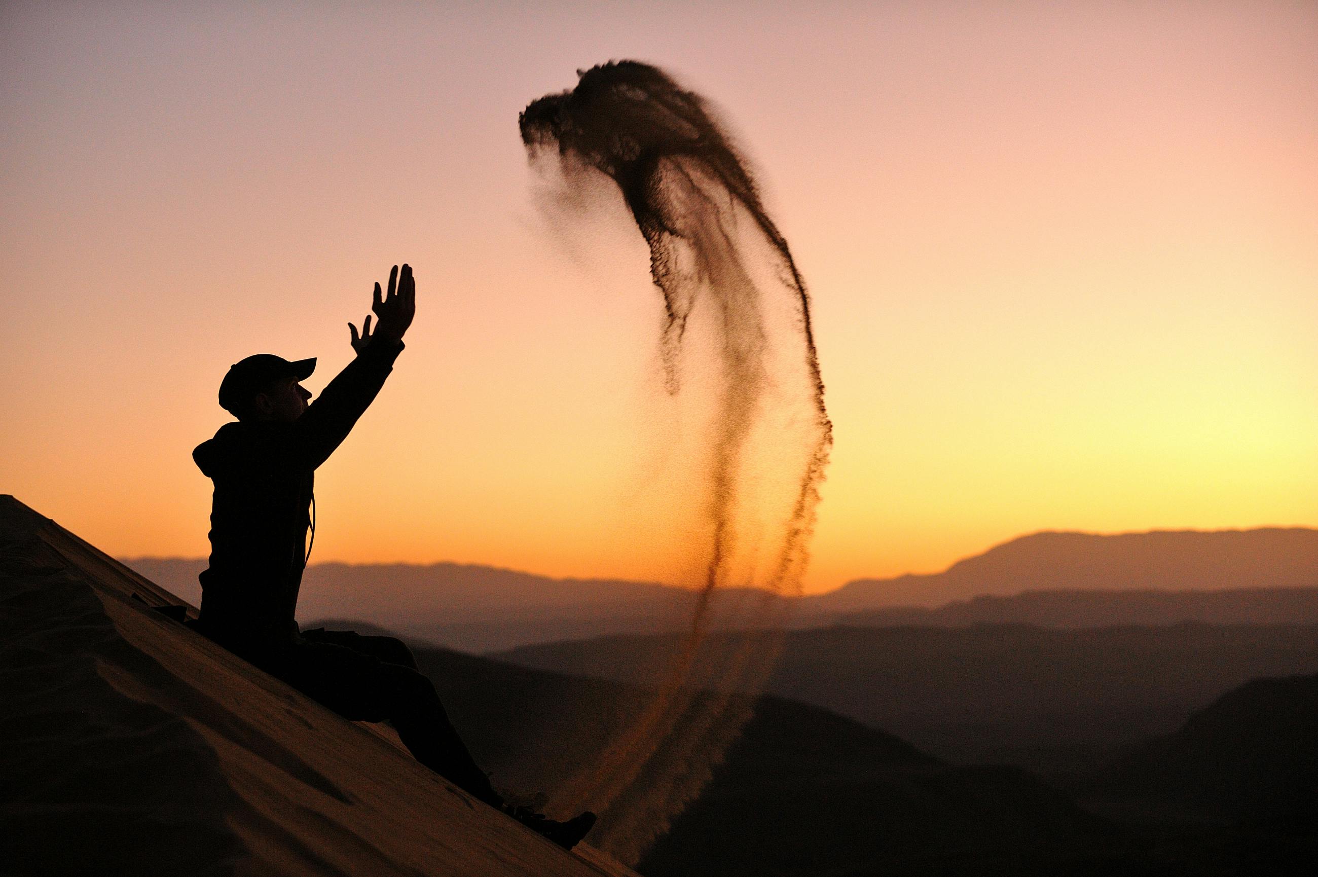 Silhouette of Man Sitting and Playing With Sand at Sunset · Free Stock ...