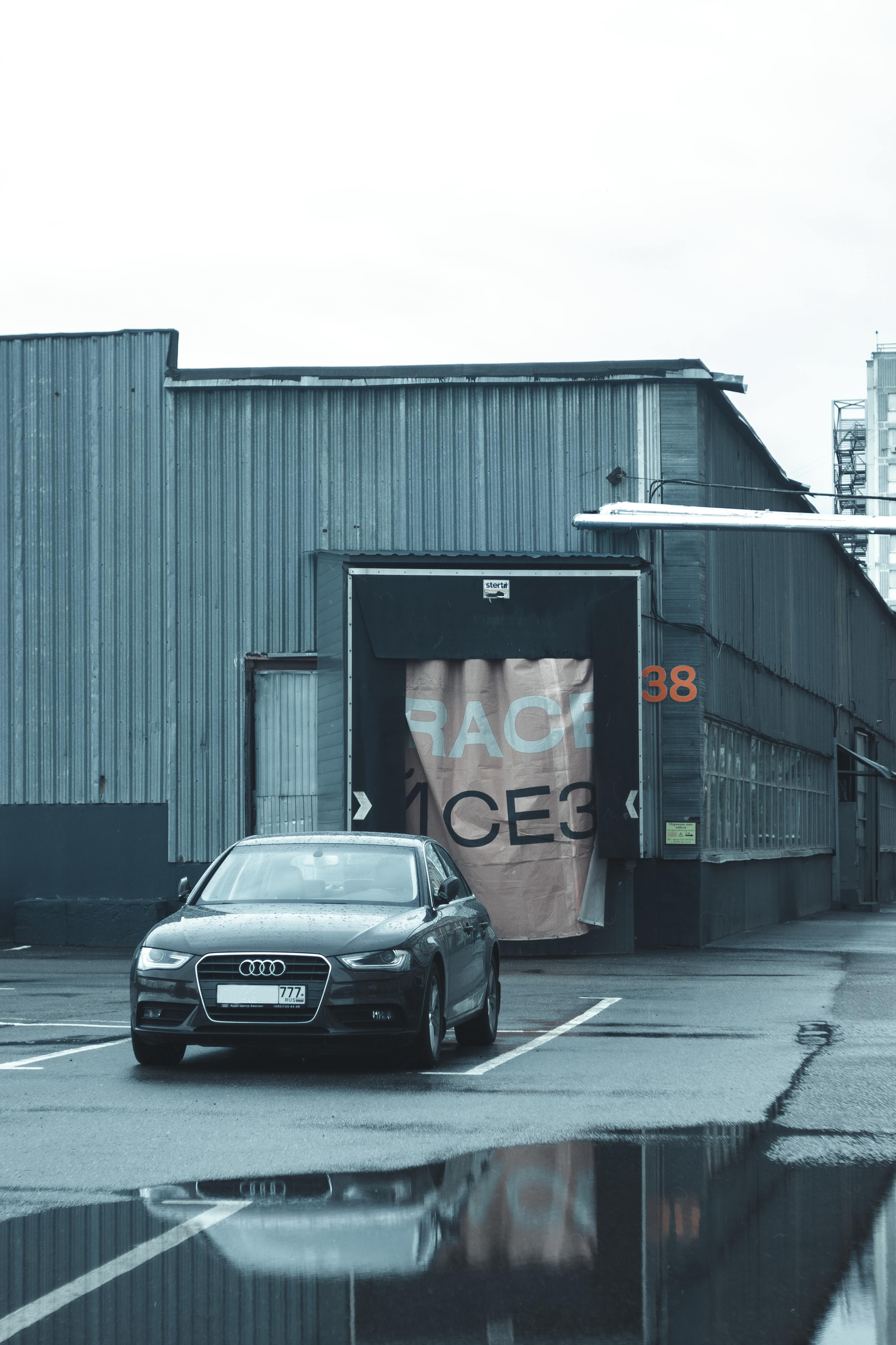 A Blue Audi Car Parked Outside the Audi Building · Free Stock Photo