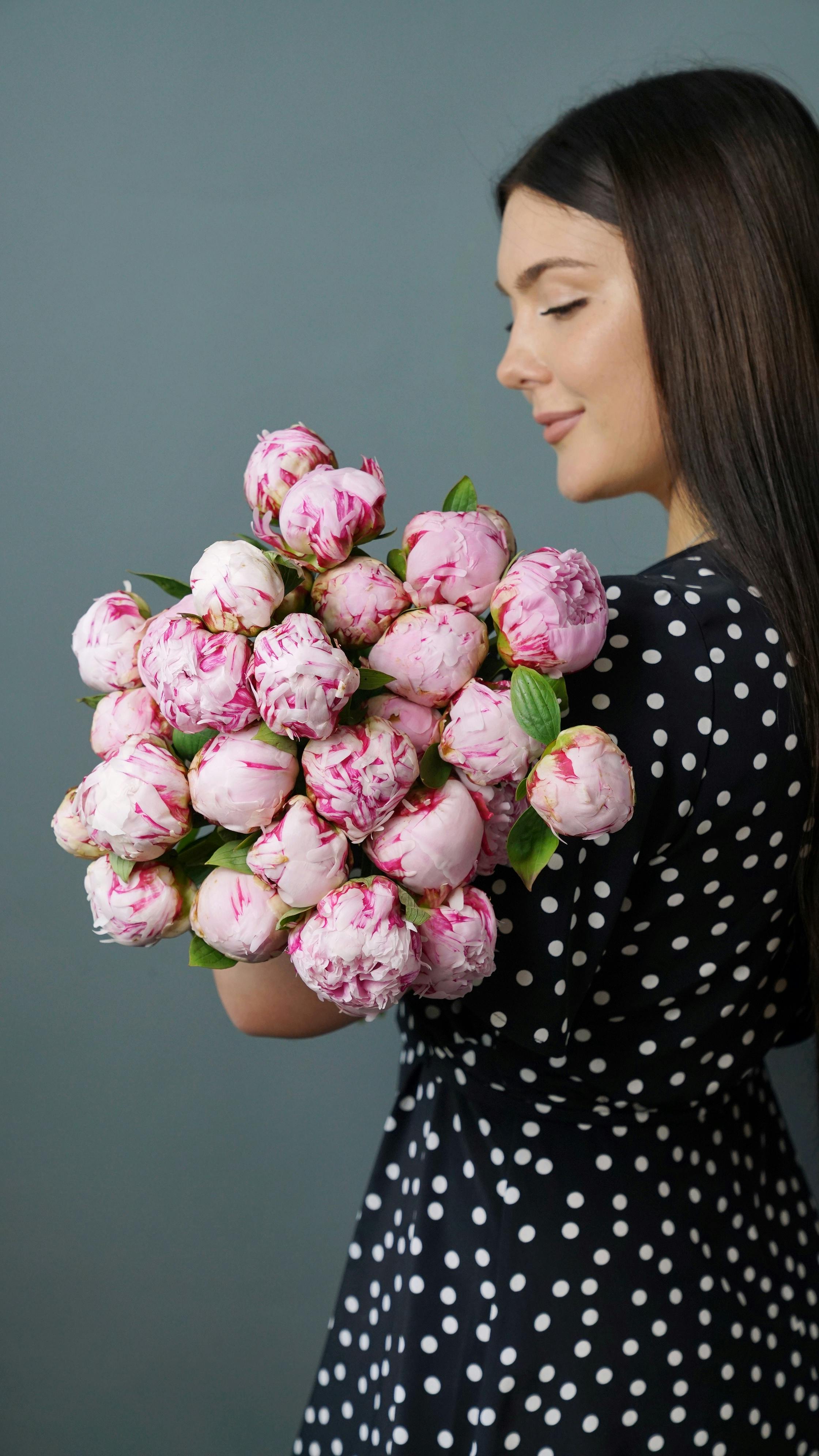 Woman Sitting in Open Field with Bouquet of Red Flowers · Free Stock Photo