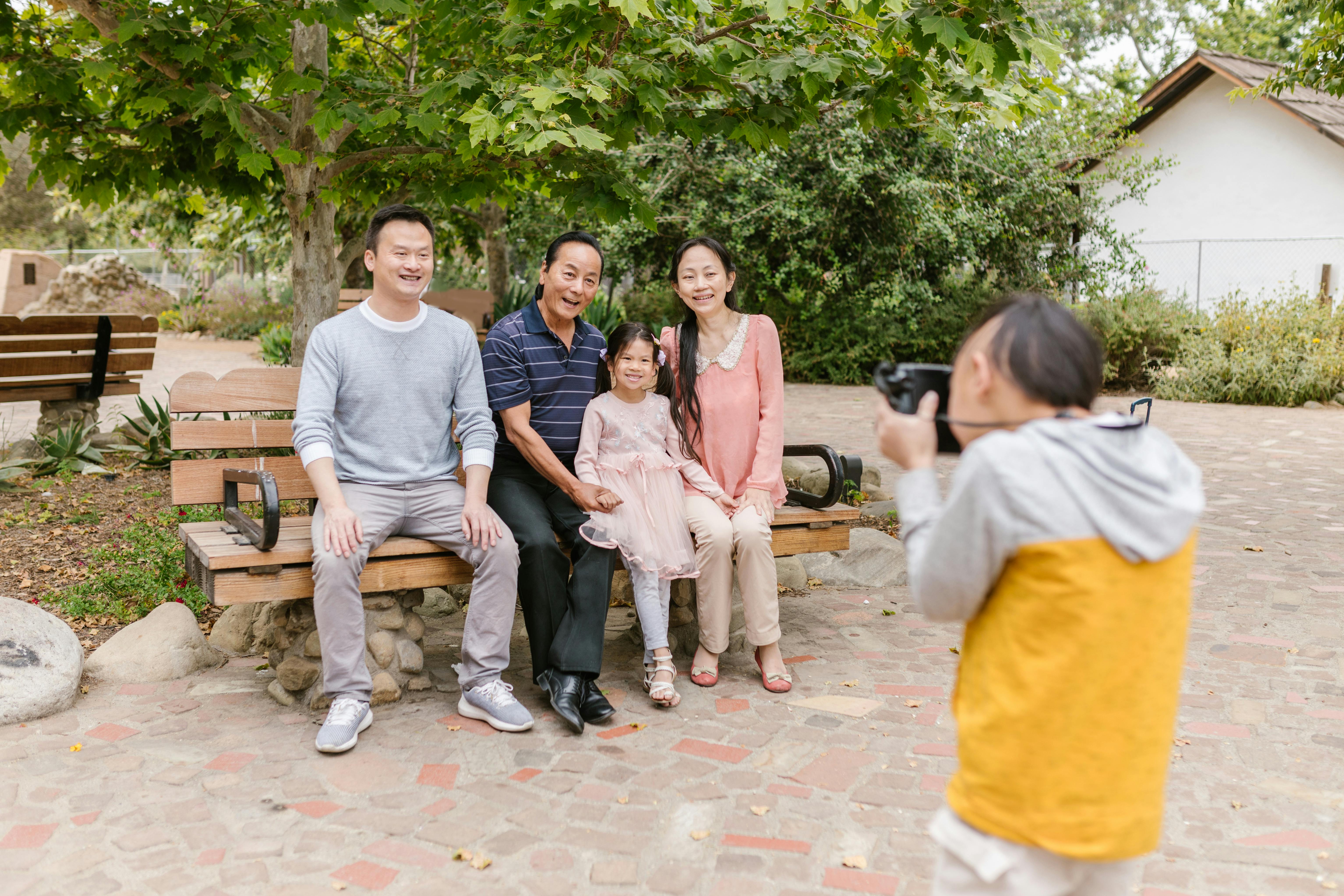 A Boy Taking a Picture of a Family Sitting on a Bench · Free Stock Photo