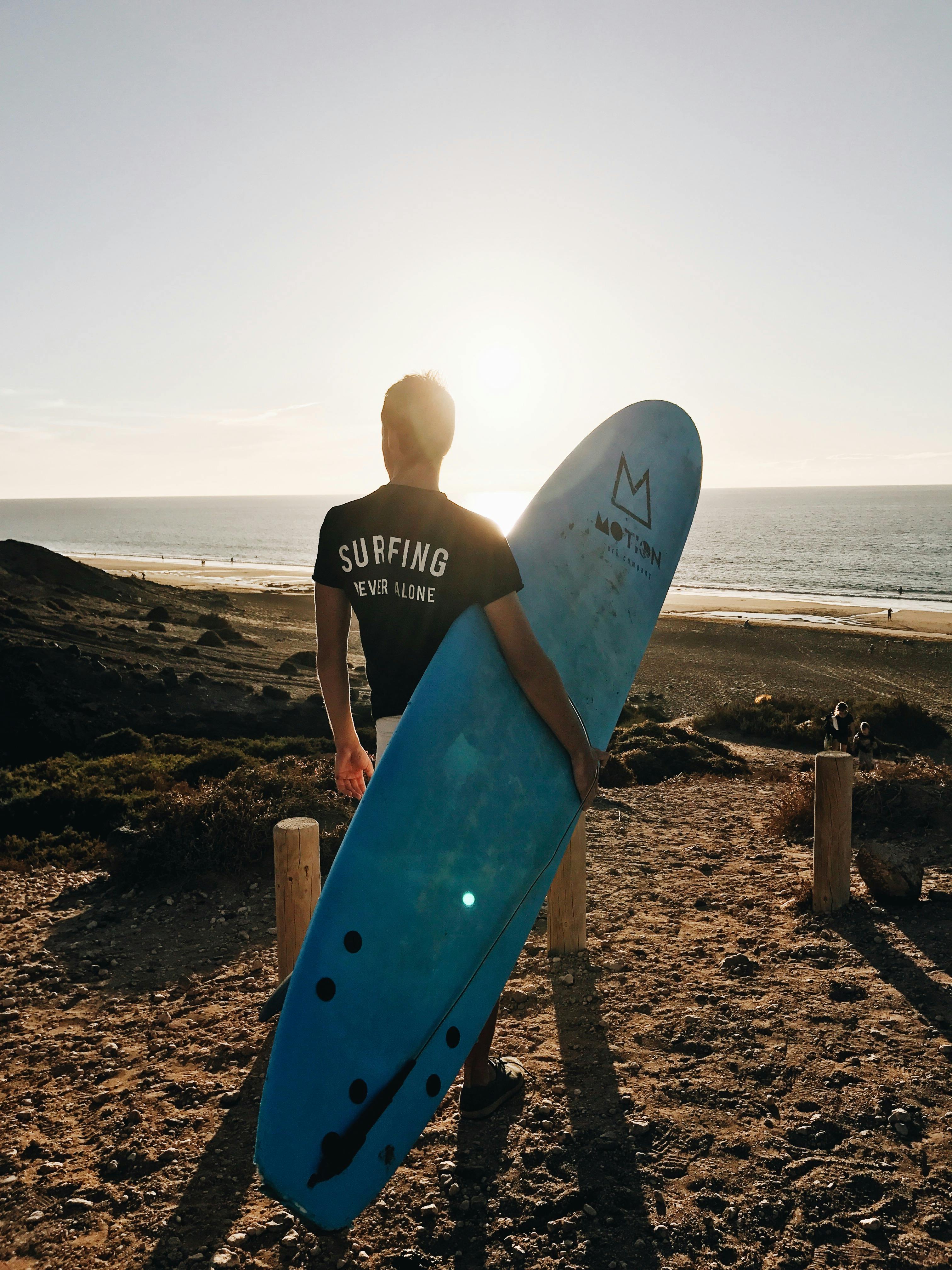Man with a Surfboard on a Beach · Free Stock Photo