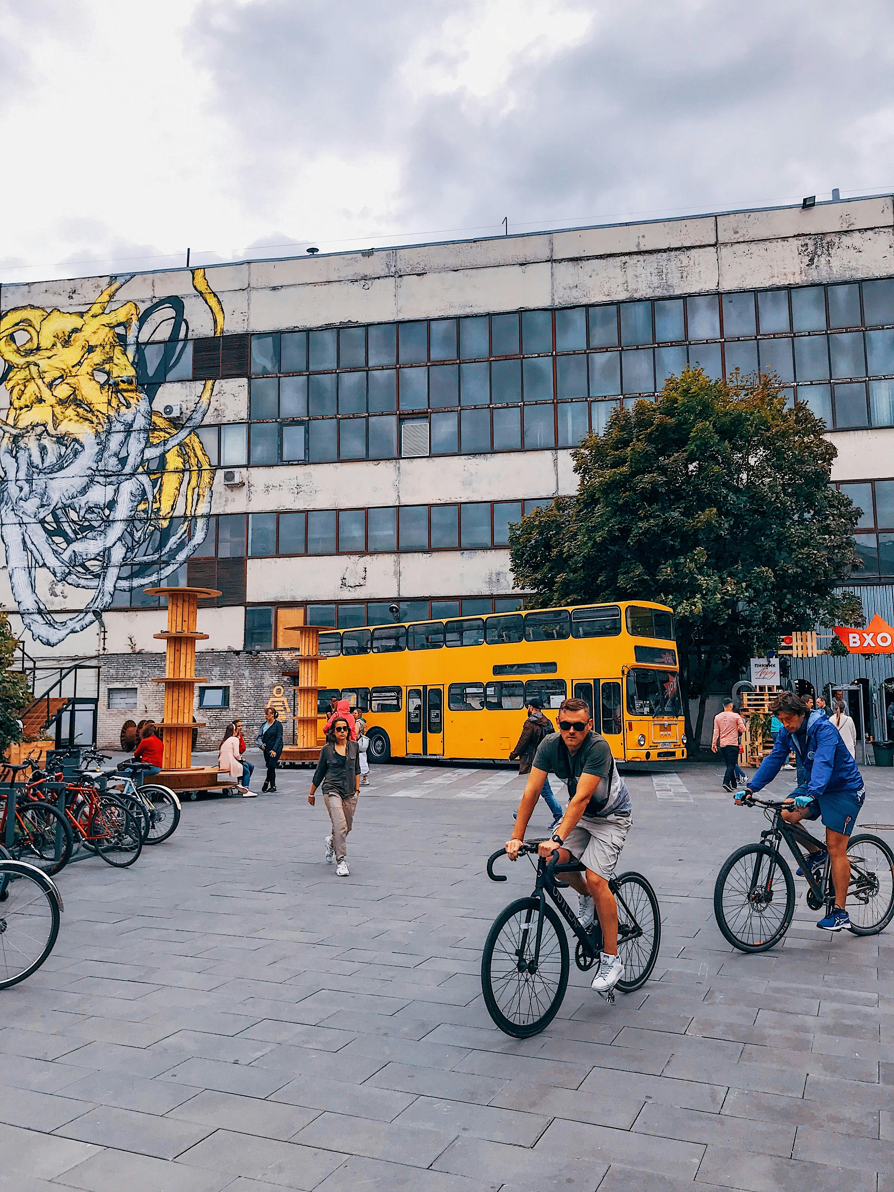People Riding Bicycle near White Concrete Building · Free Stock Photo