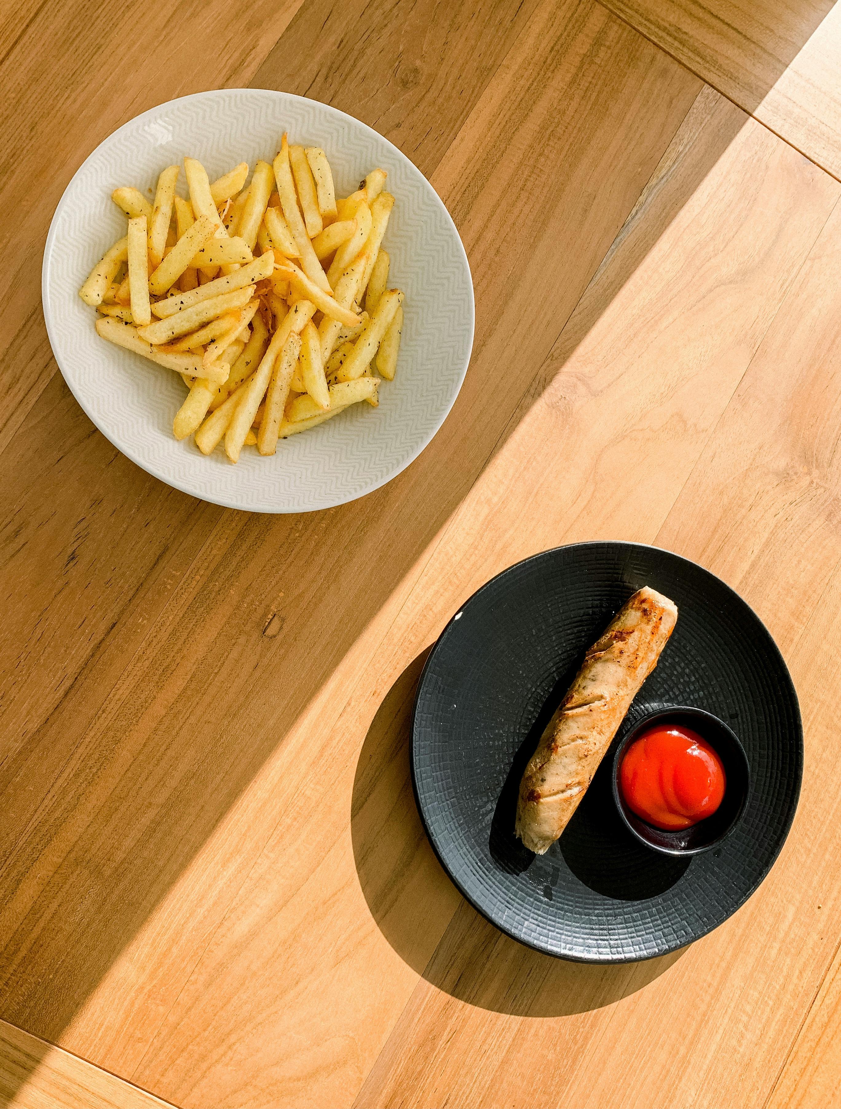 Top Diagonal View of Chips and Sausage on Plates · Free Stock Photo