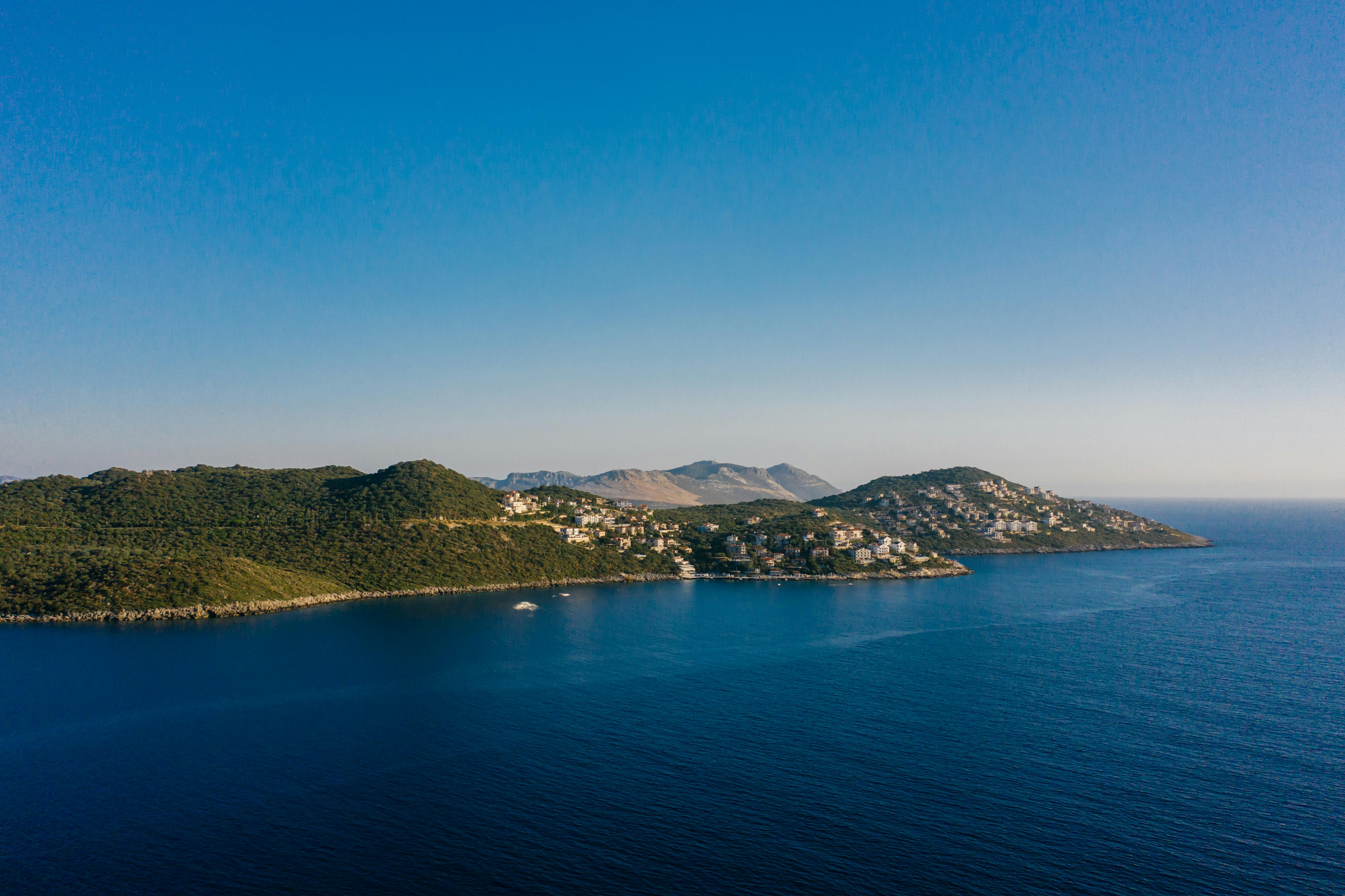 Green Mountain Beside Blue Sea Under Blue Sky · Free Stock Photo